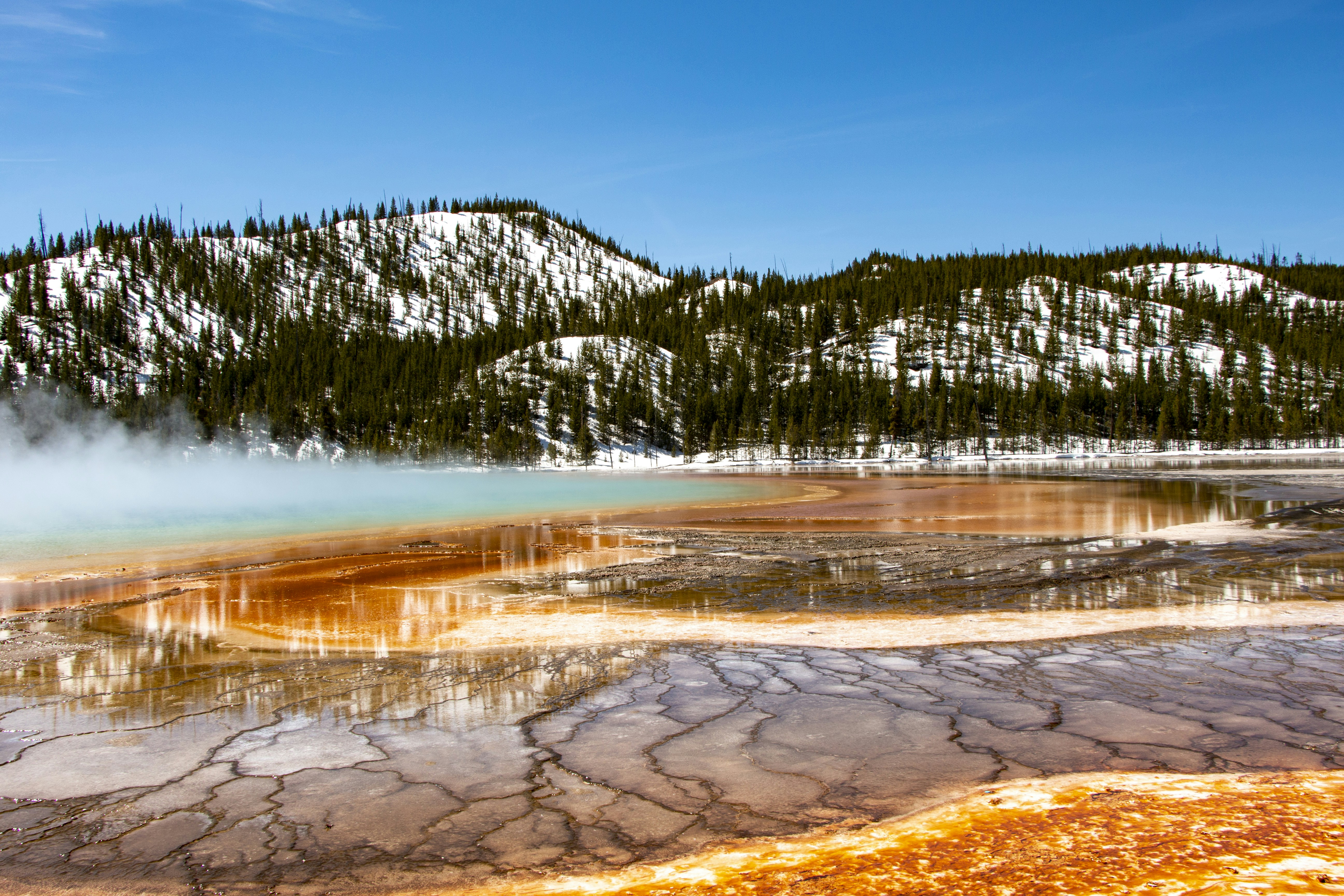 Terraced Steamscape: Orange Pools Under a Snowy Alpine Sky