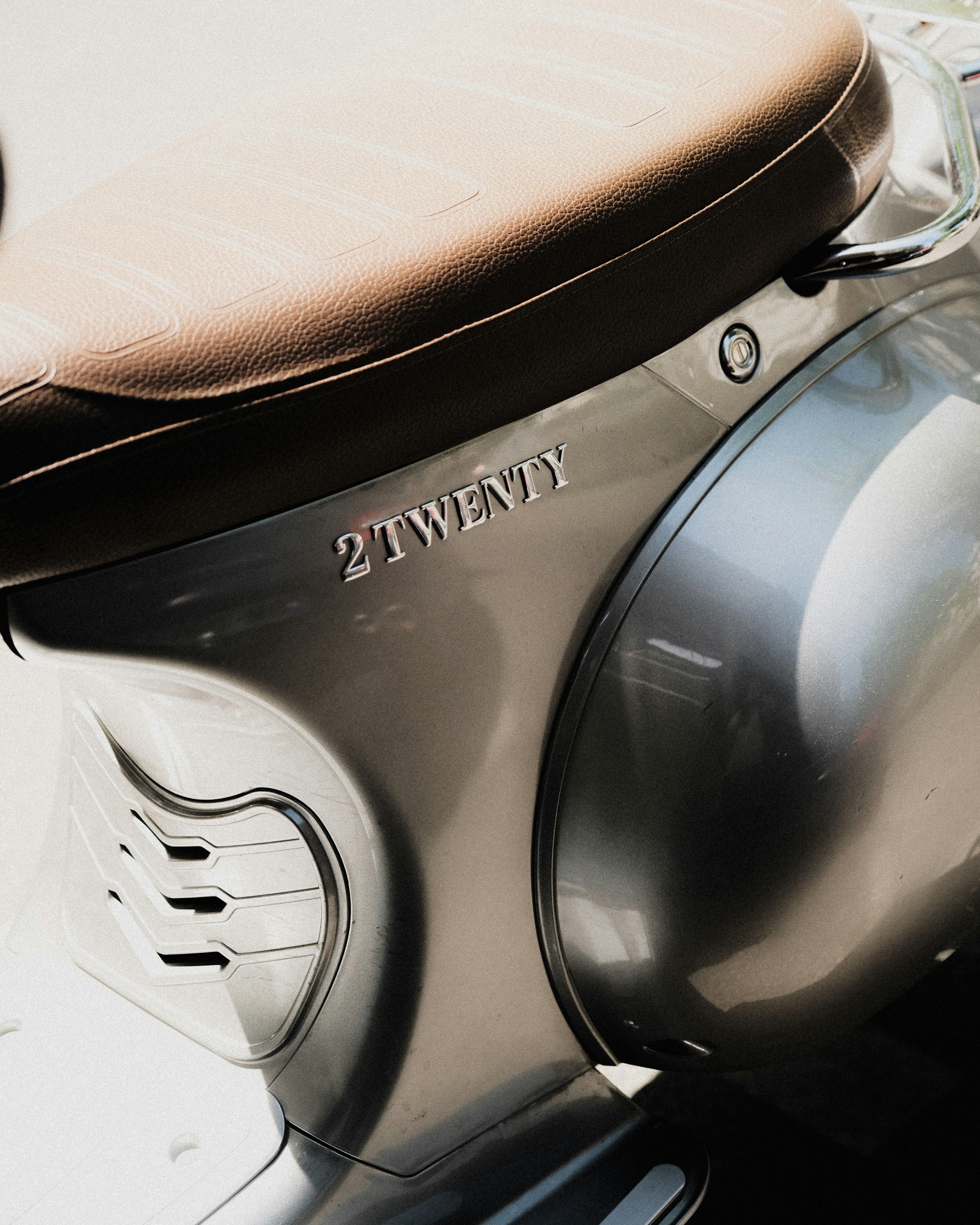 The 2TWENTY badge gleams on a retro scooter's curved panel.