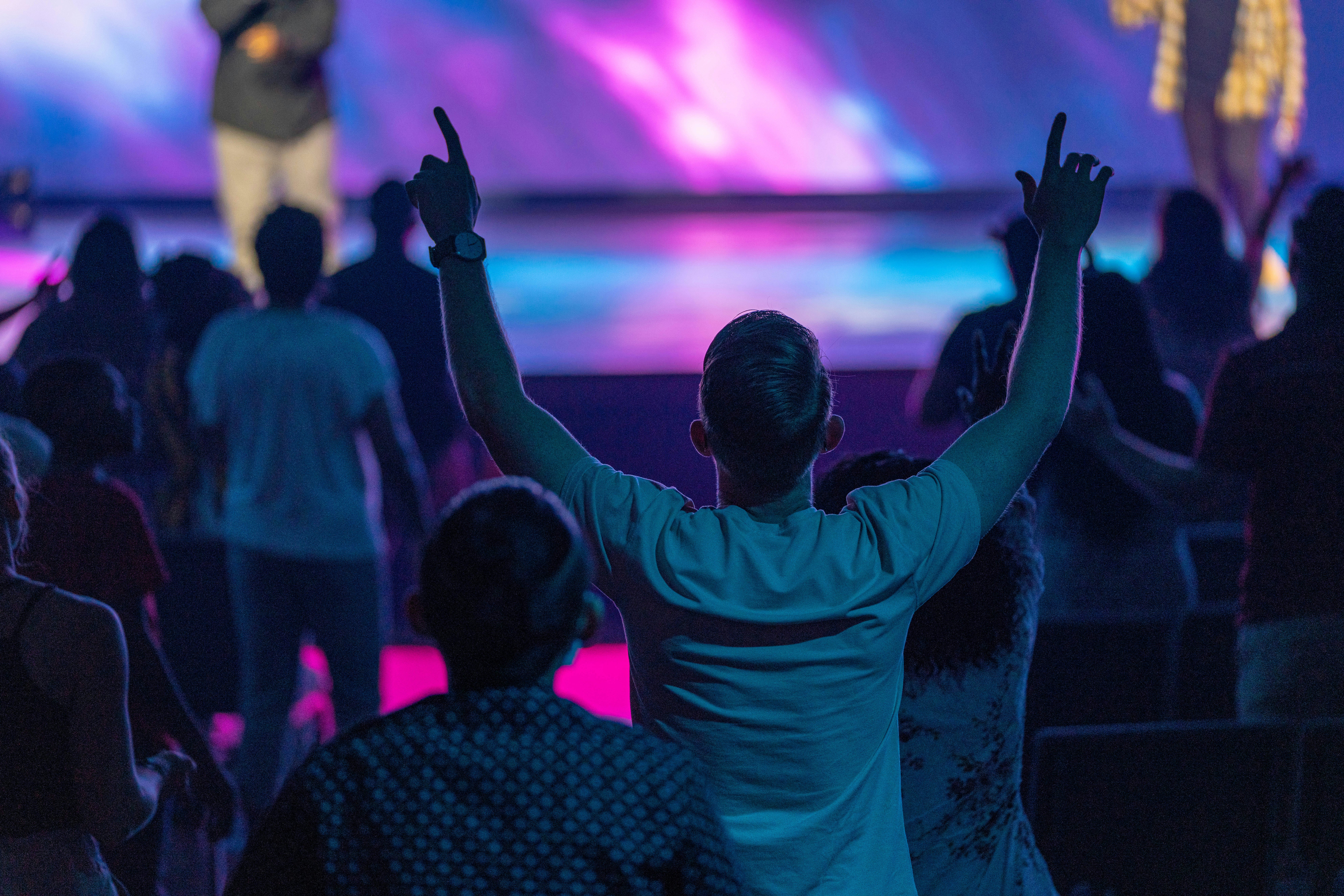 Neon Reverie: Hands Lift Against the Violet Stage Pulse