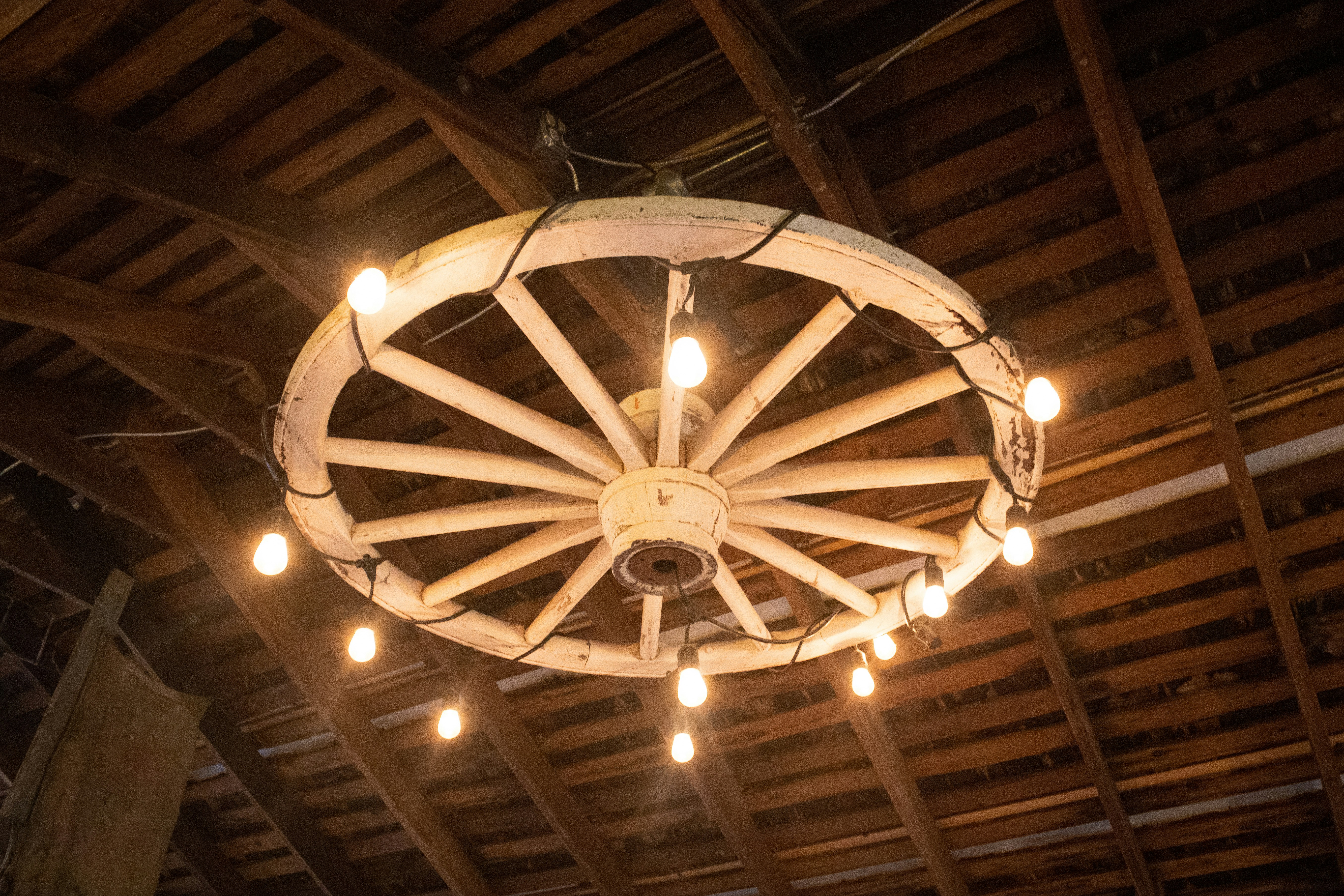 Circular chandelier of warm bulbs suspended beneath timber rafters