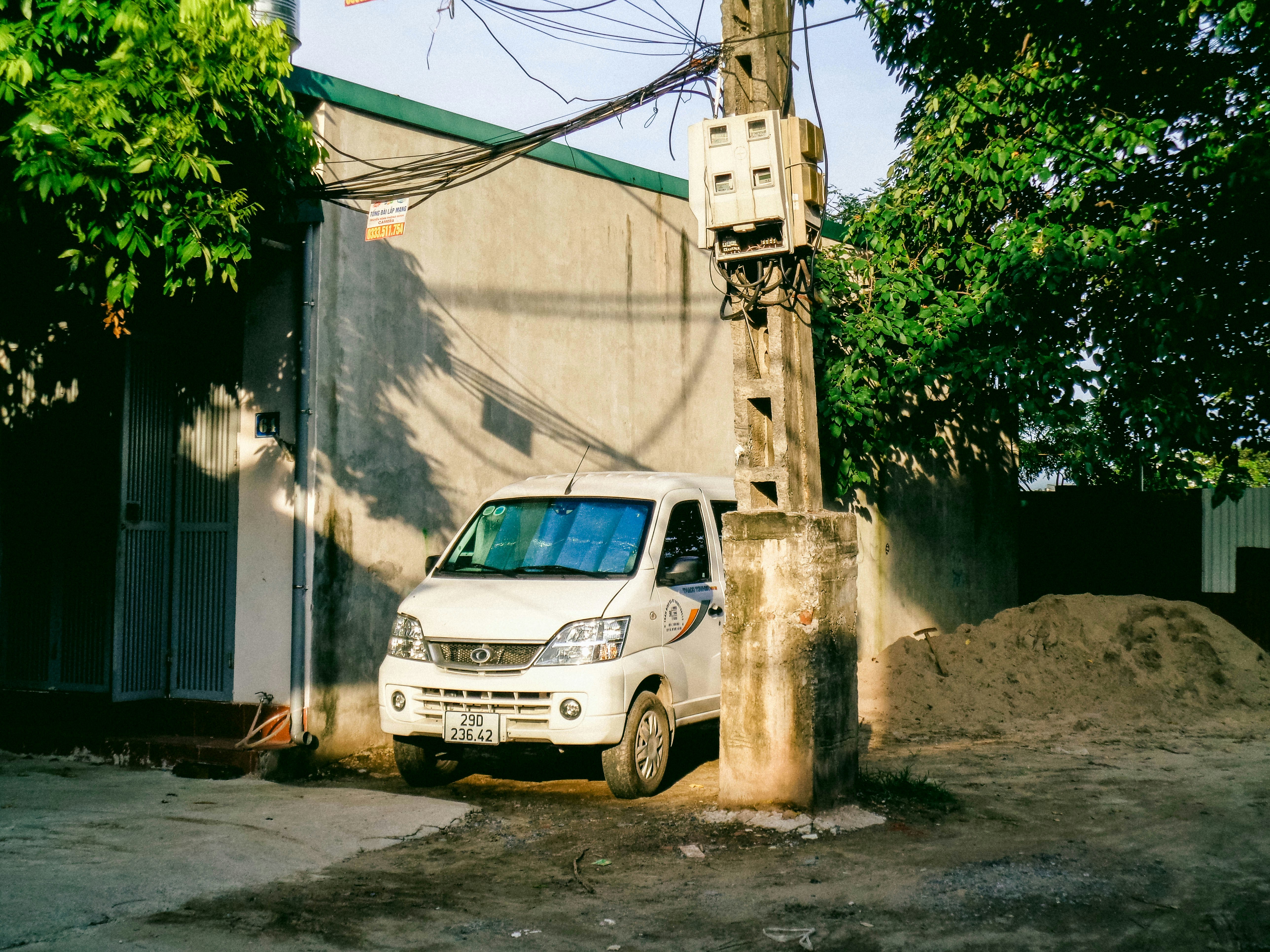 White van under a utility pole in a sunlit backstreet