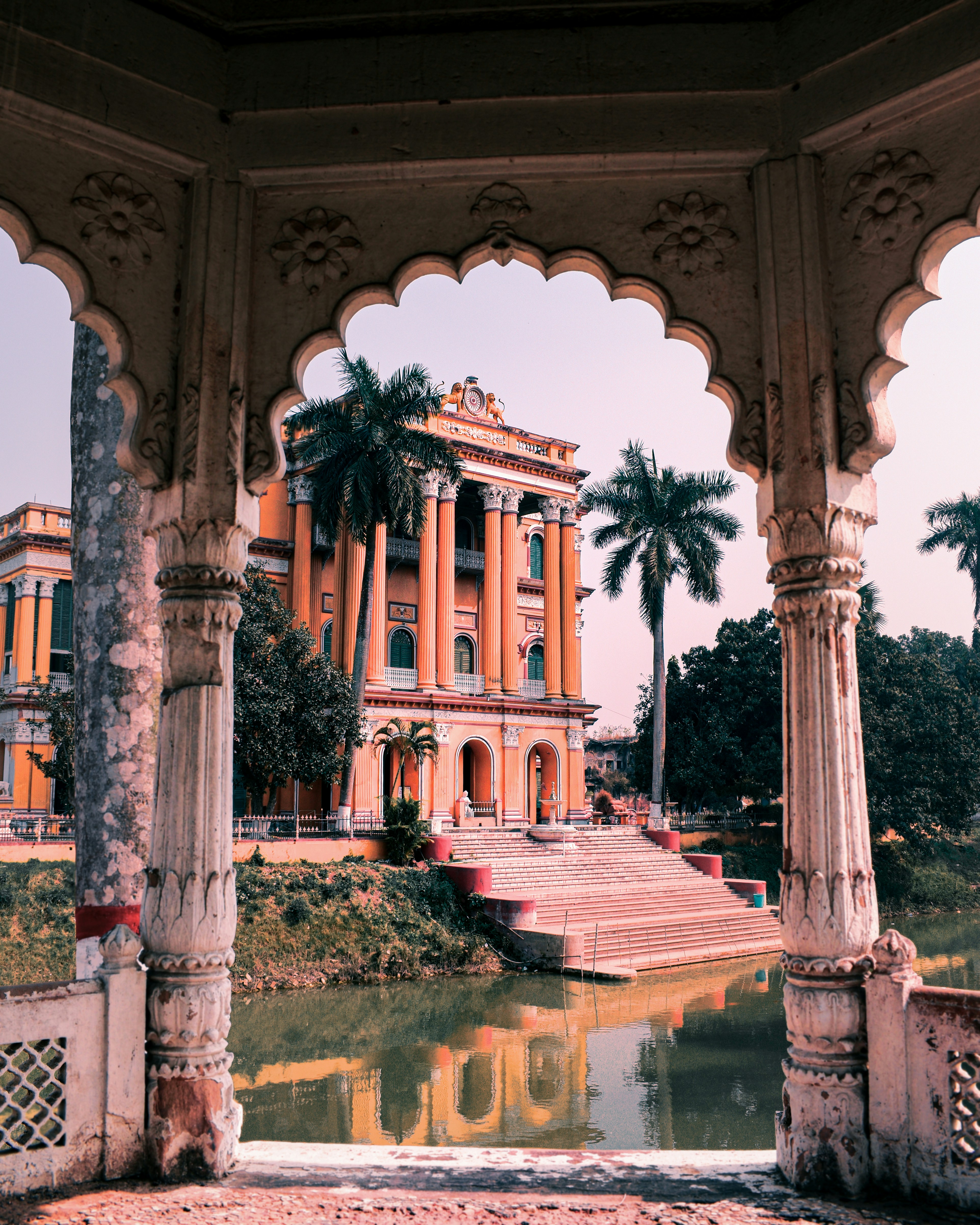 A historic building framed by ornate architecture, reflecting its vibrant colors in the serene waters below.