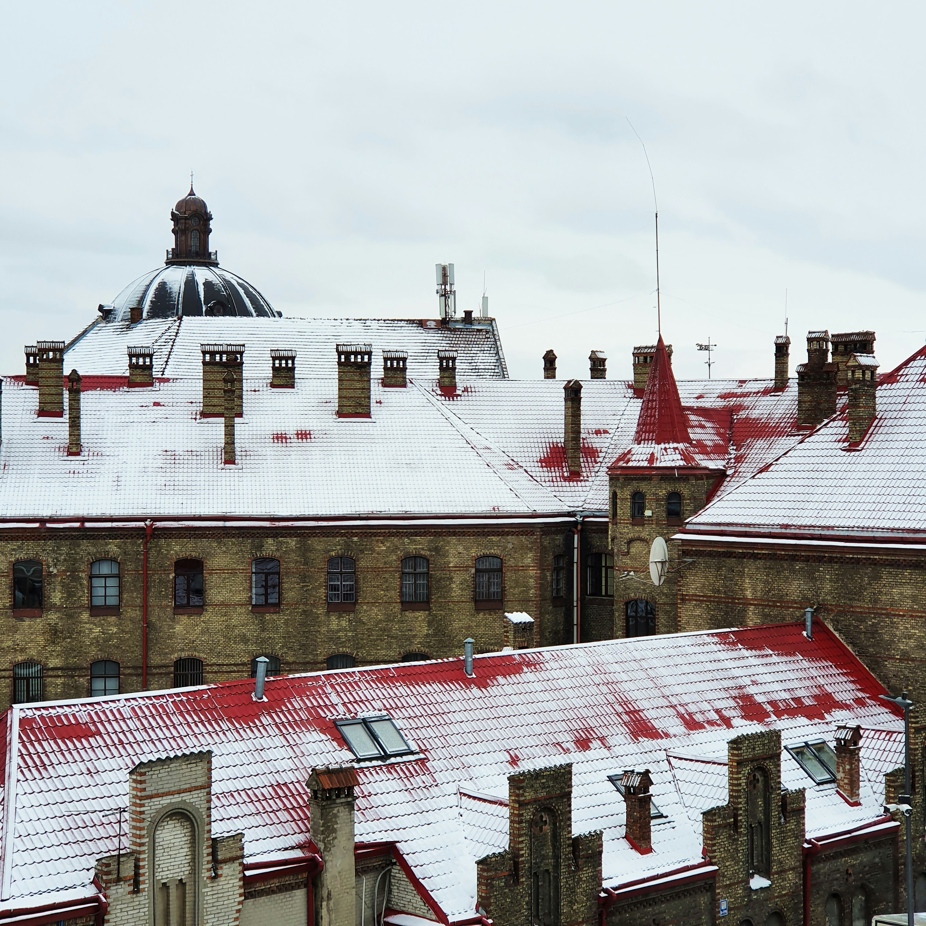 Snow-touched Red Roofs Under a Distant Dormer Sky