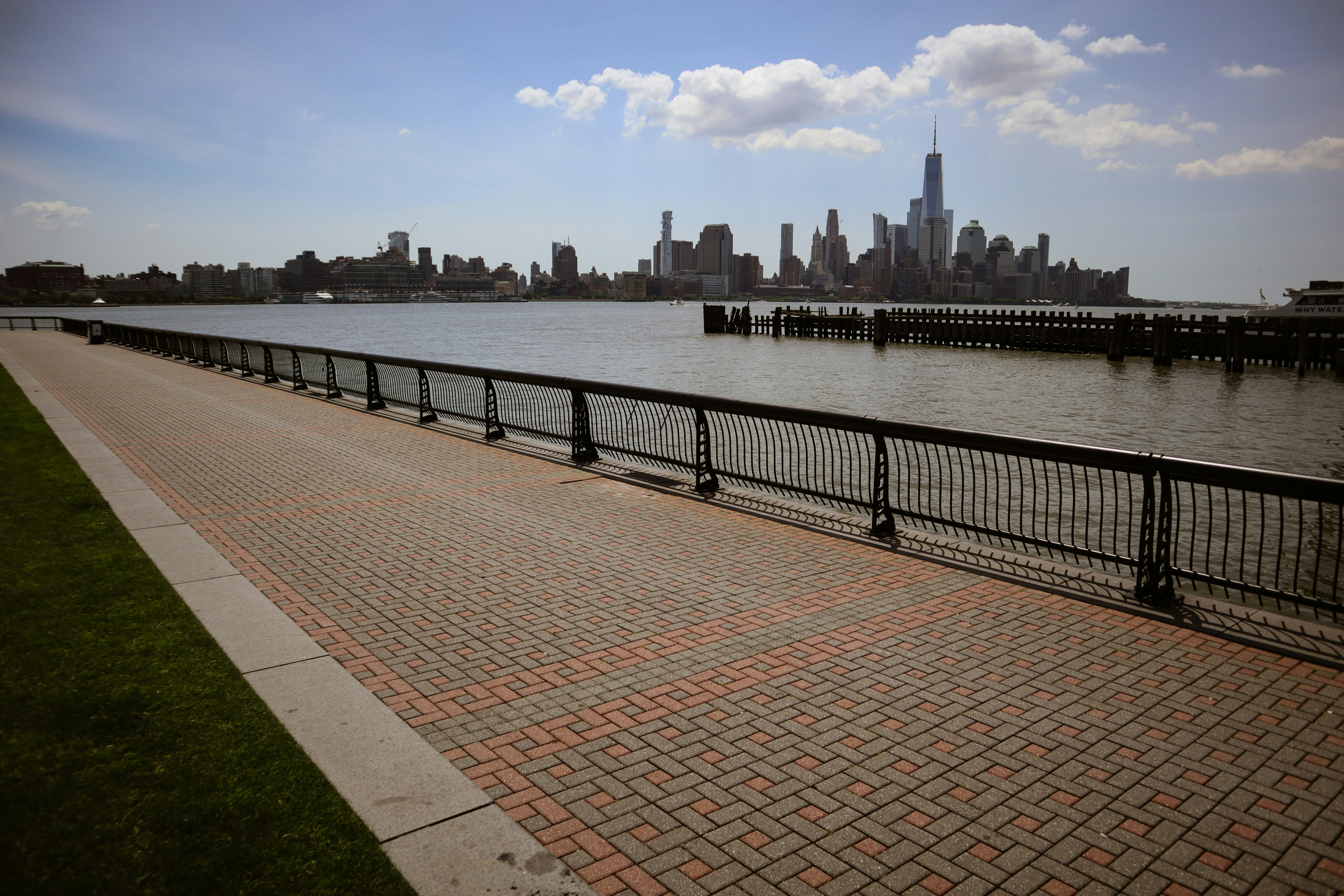 a brick walkway next to a body of water with a city in the background