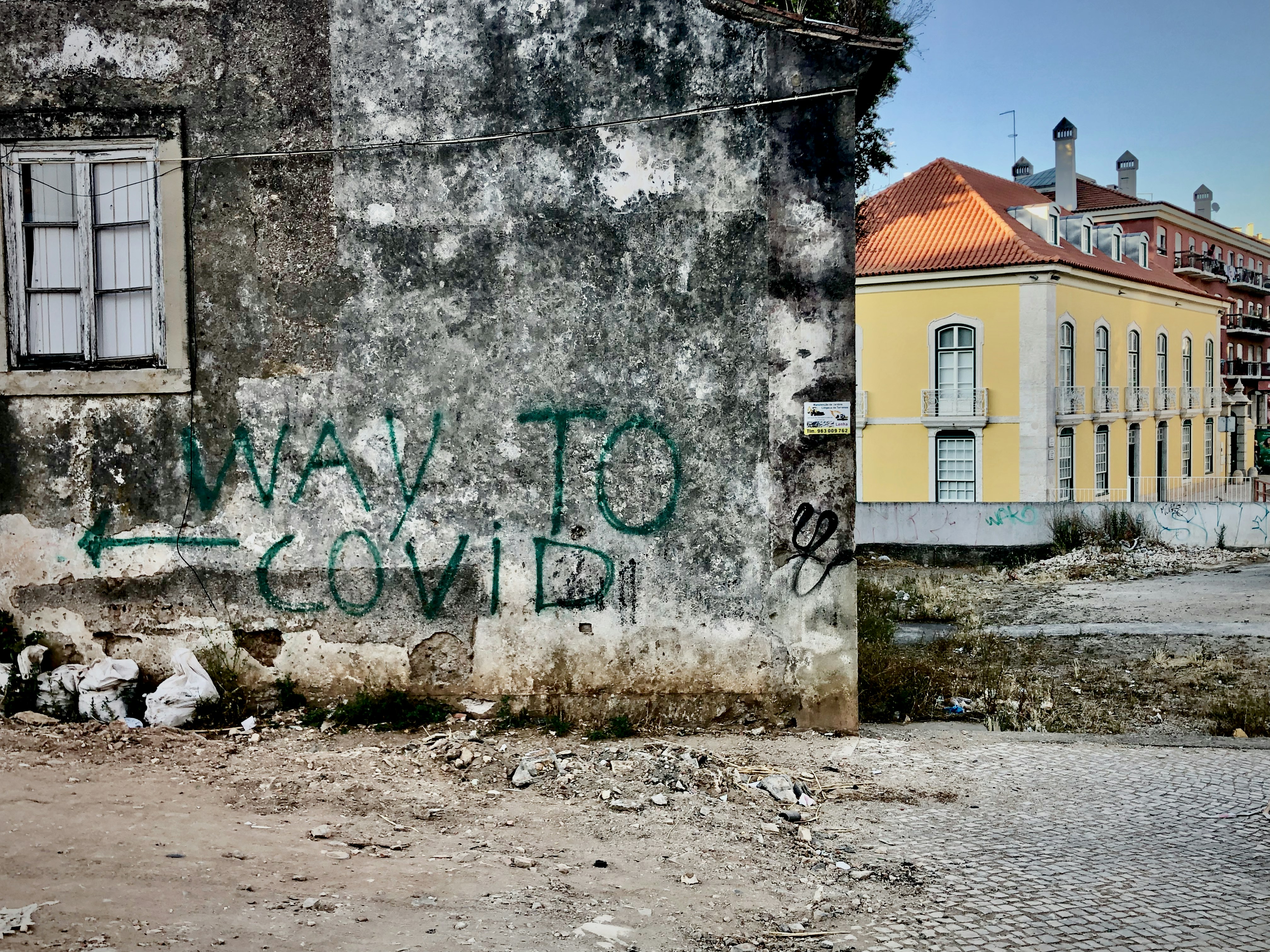 Green Graffiti and Sunlit Contrast: Weathered Wall by a Bright Yellow Facade