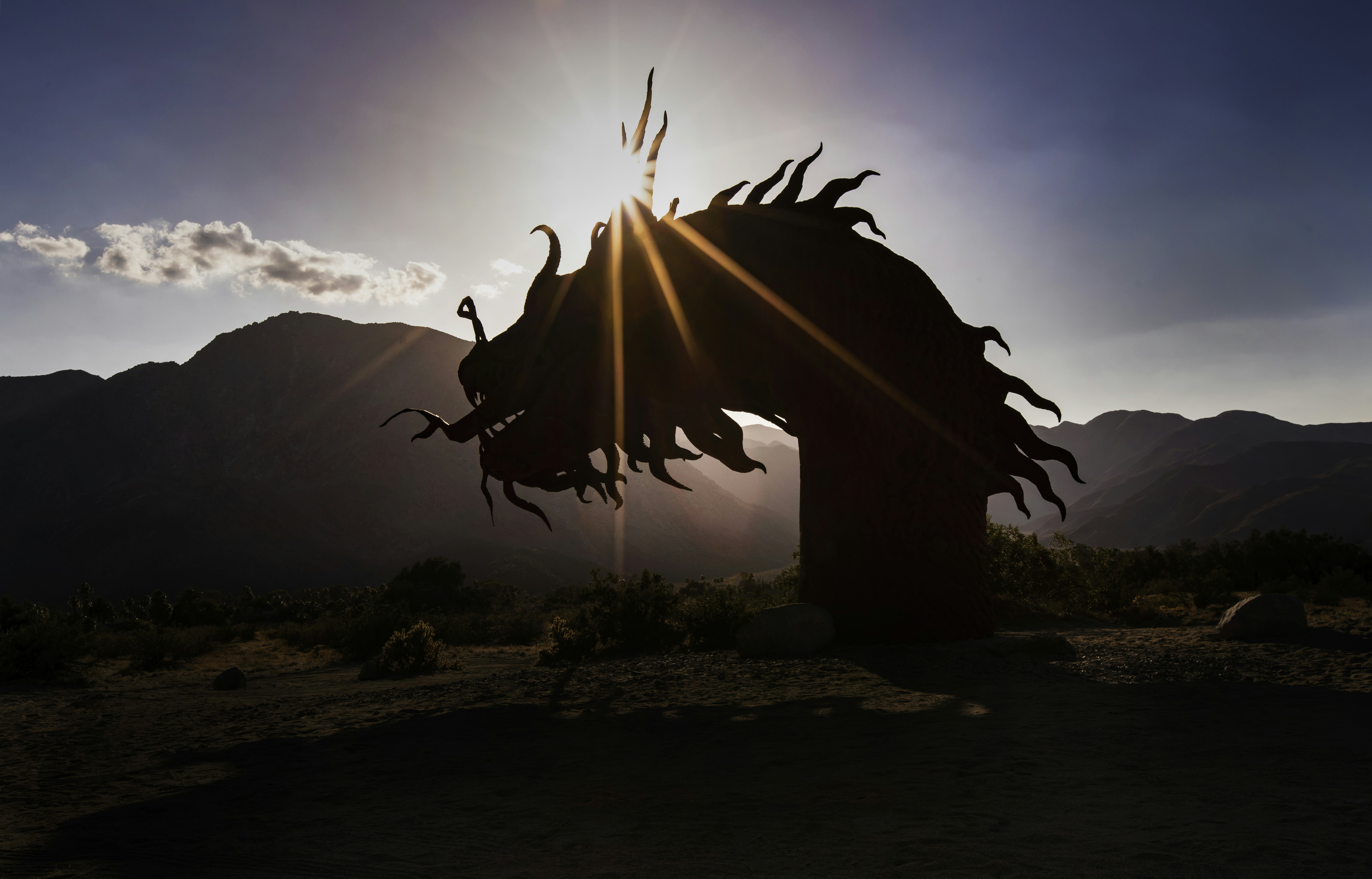 Sunburst Over Desert Dragon: Dawn Silhouette of a Dragon-Shaped Sculpture