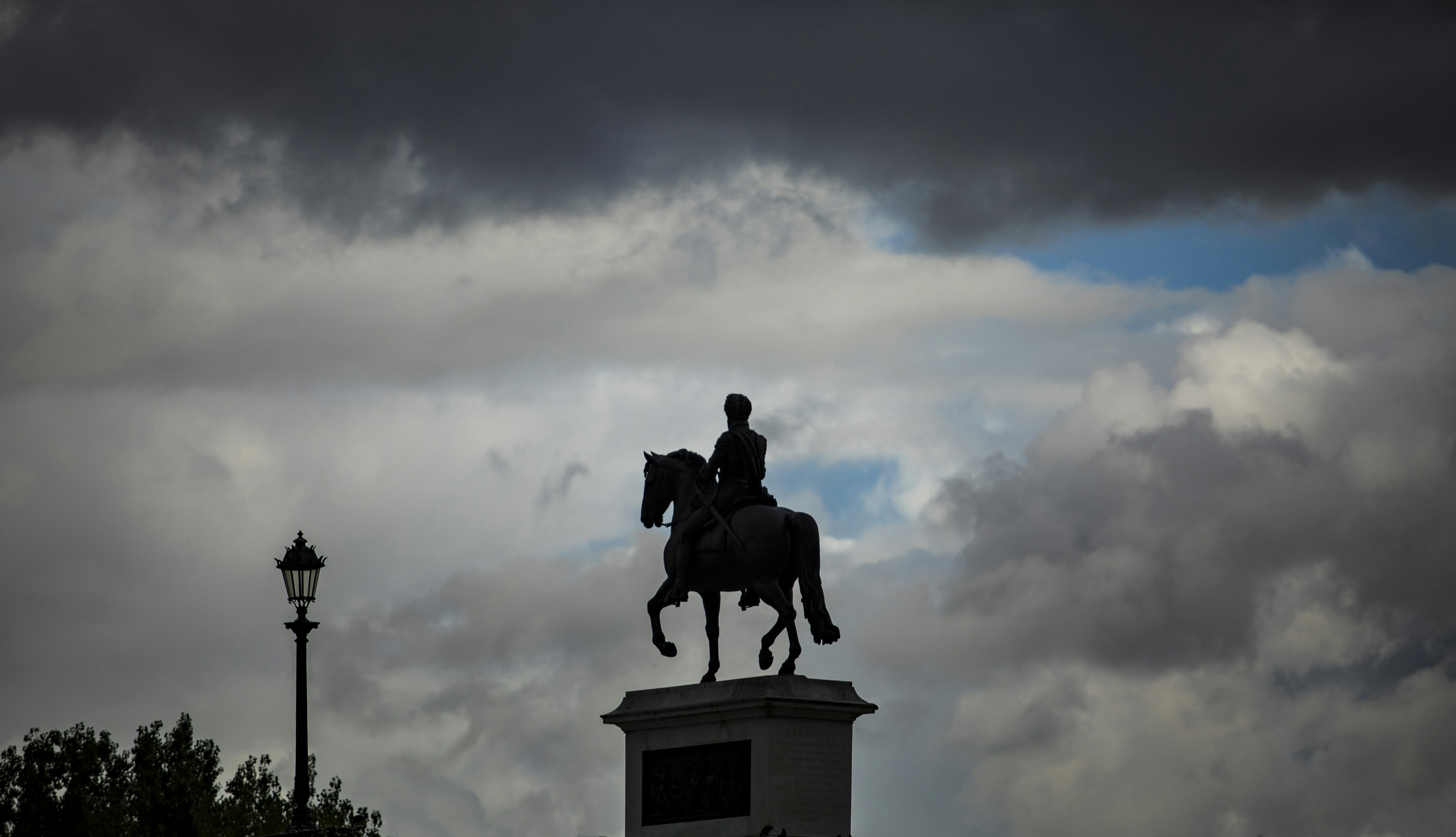 Equestrian silhouette atop a pedestal beneath a brooding, cloud-filled sky