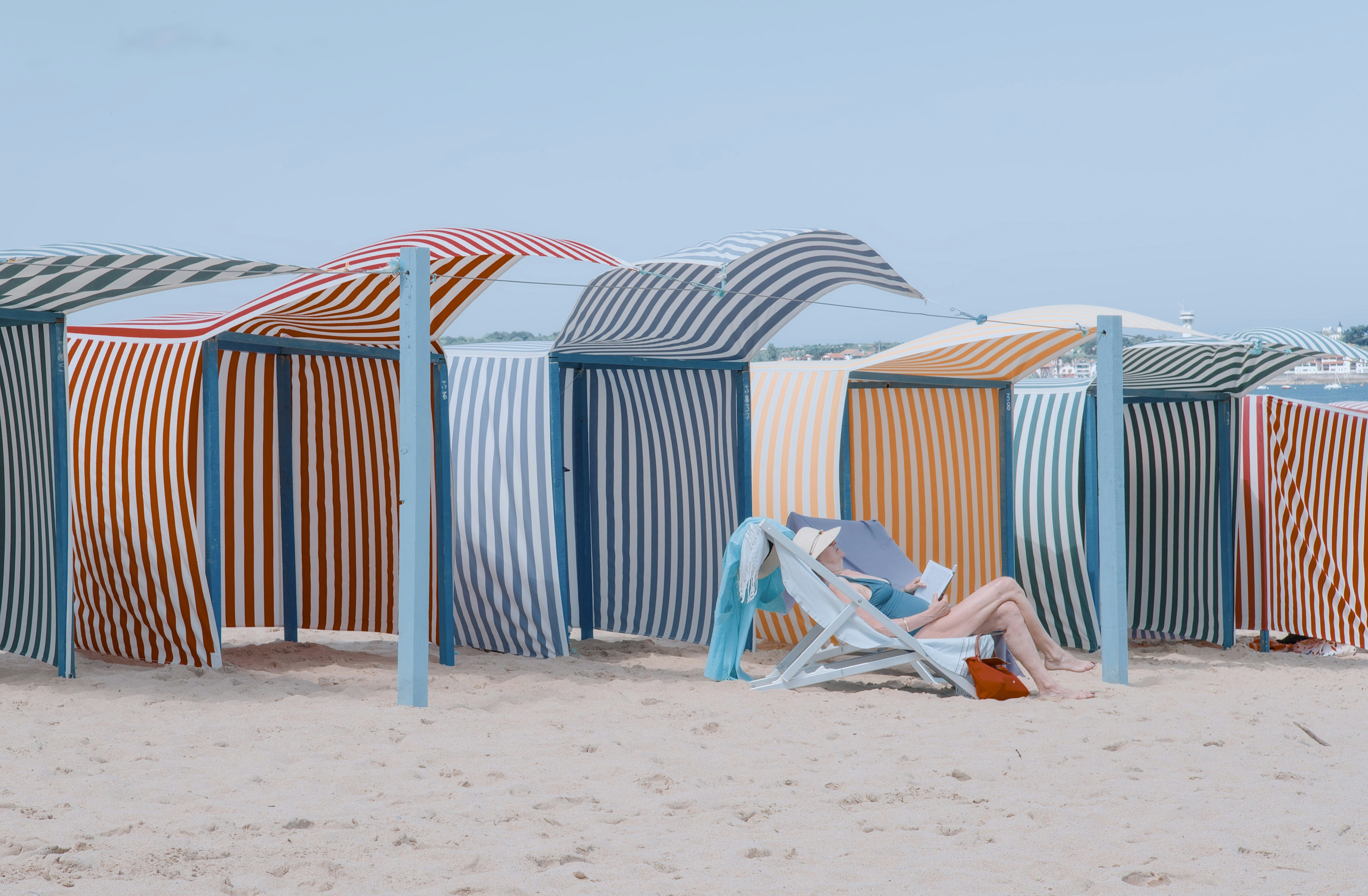 Colorful beach cabanas sway gently in the breeze, framing a serene scene of relaxation on the sandy shore.