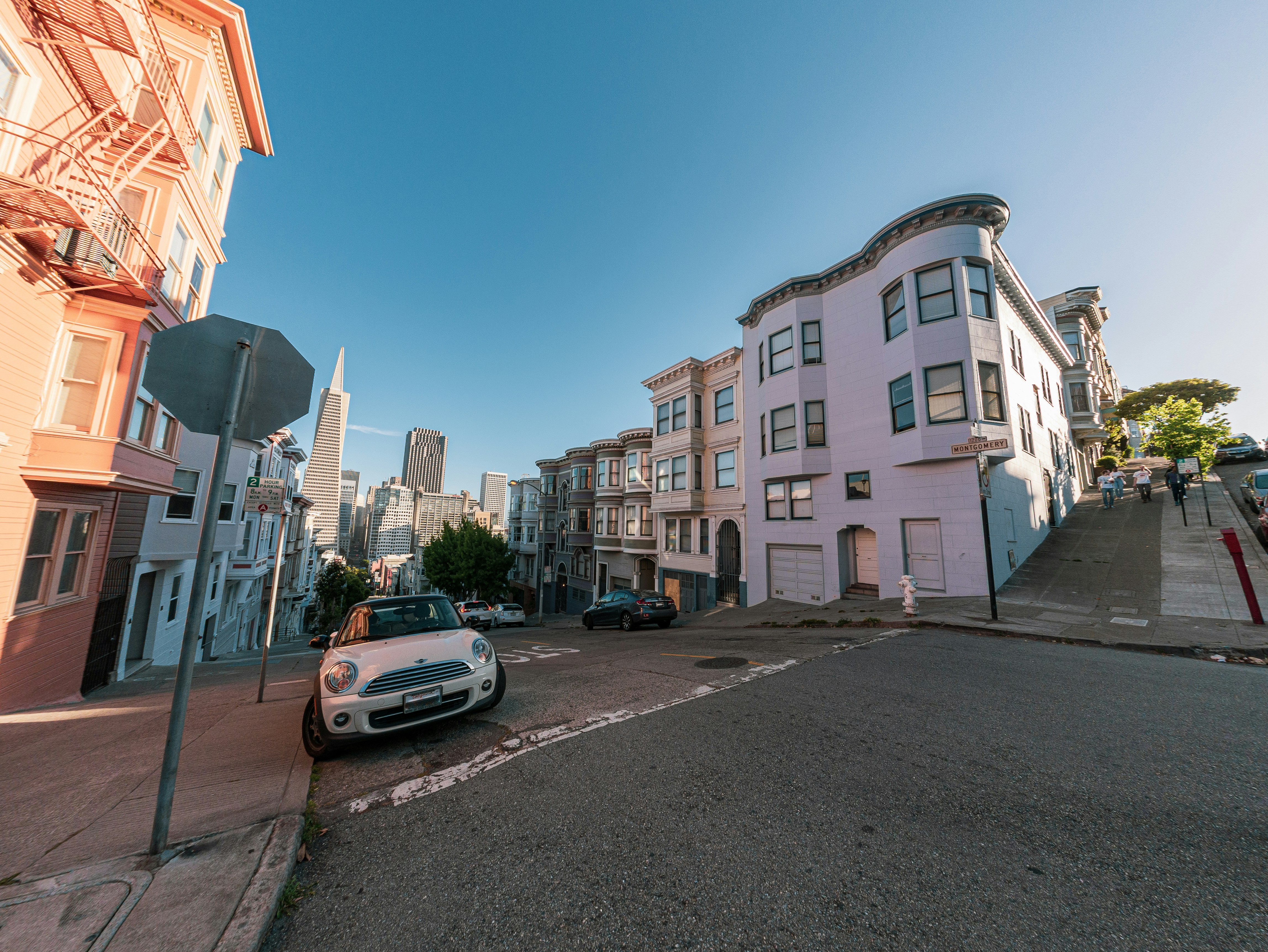 A steep street with cars and colorful buildings under a clear blue sky.