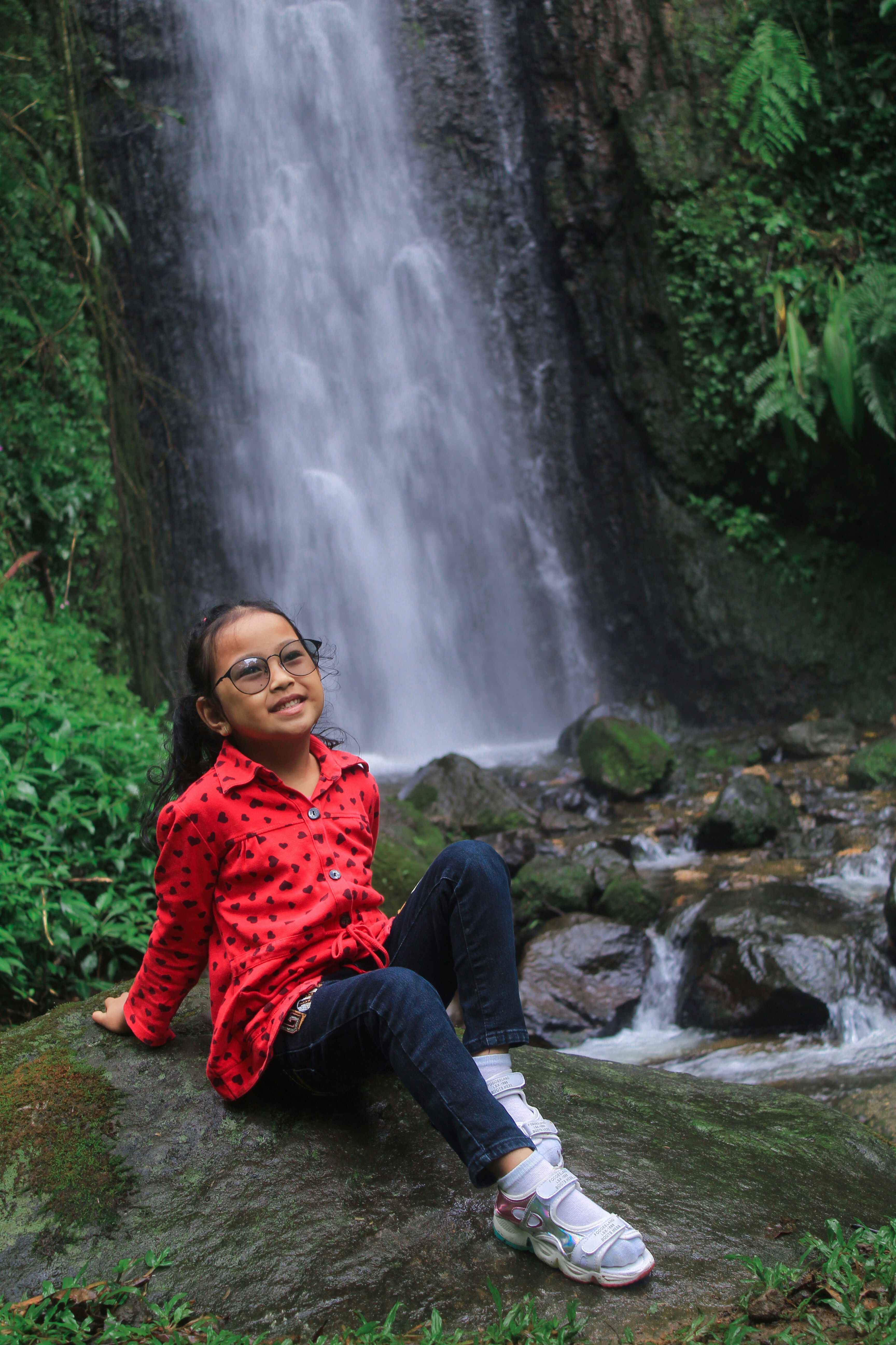 Une personne assise sur un rocher près d’une cascade photo – Image ...
