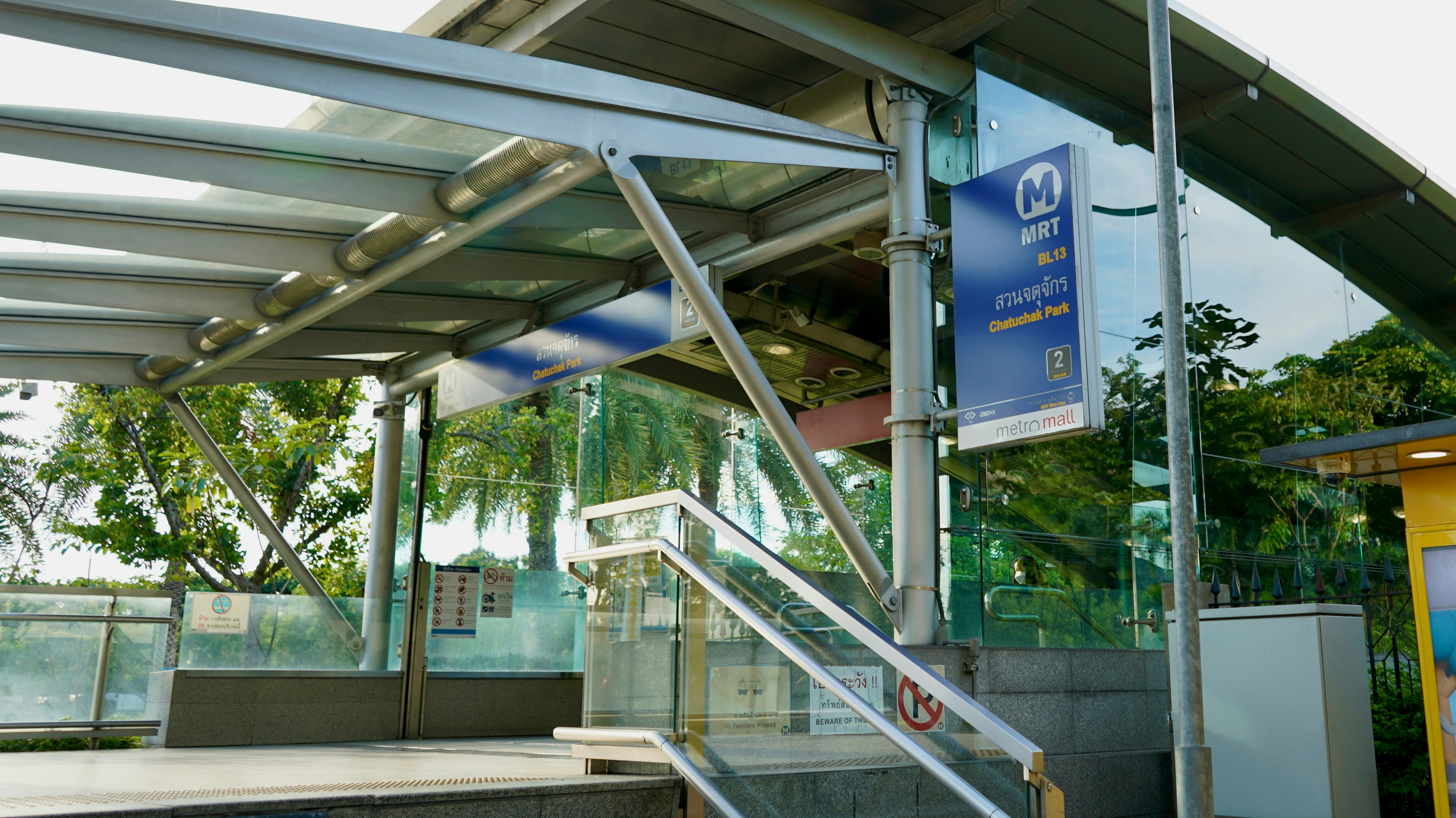 Modern MRT station entrance showcasing sleek architecture and surrounding greenery.