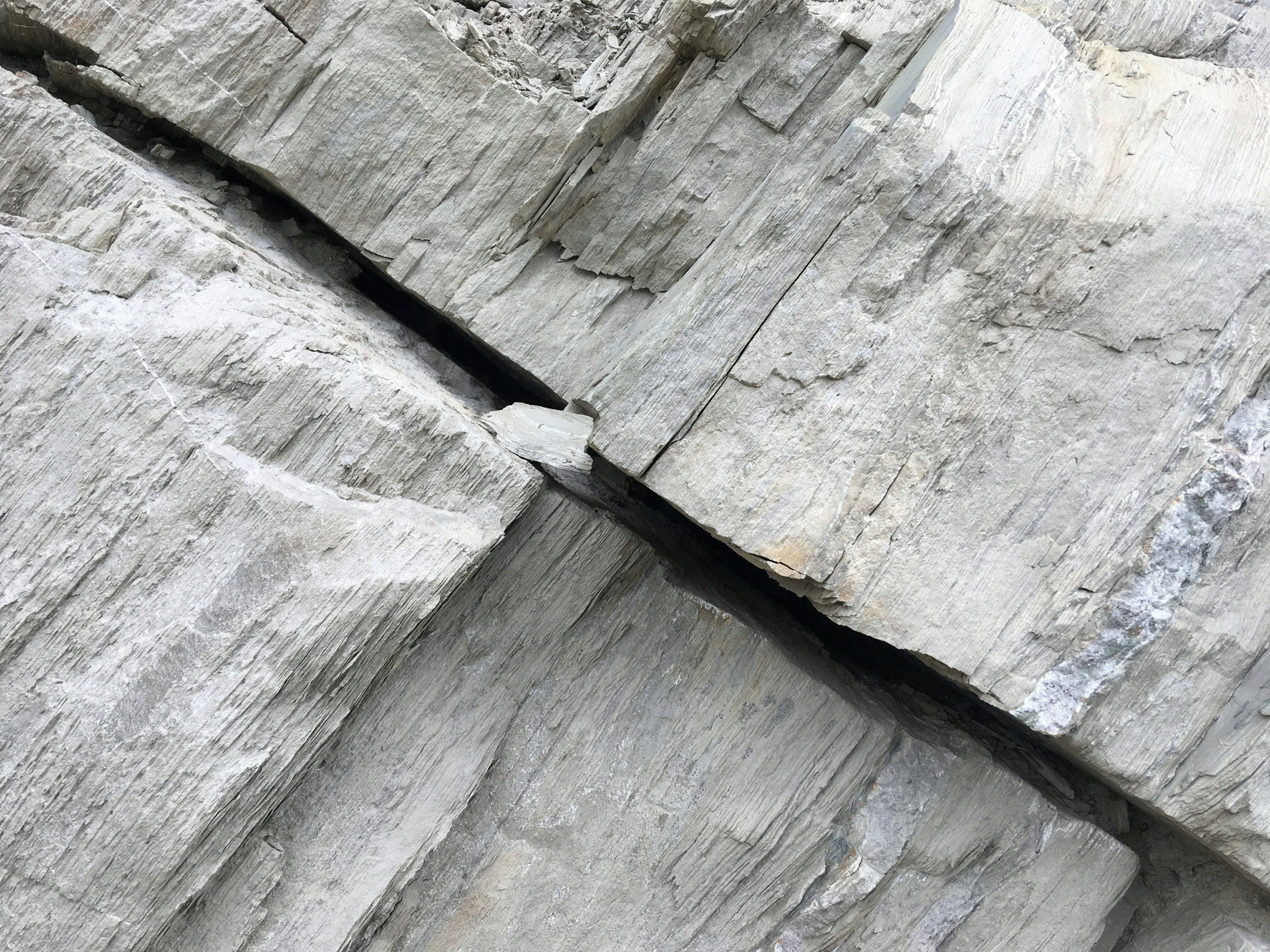 Small rock wedged tightly between two large stone slabs, highlighting natural tension.
