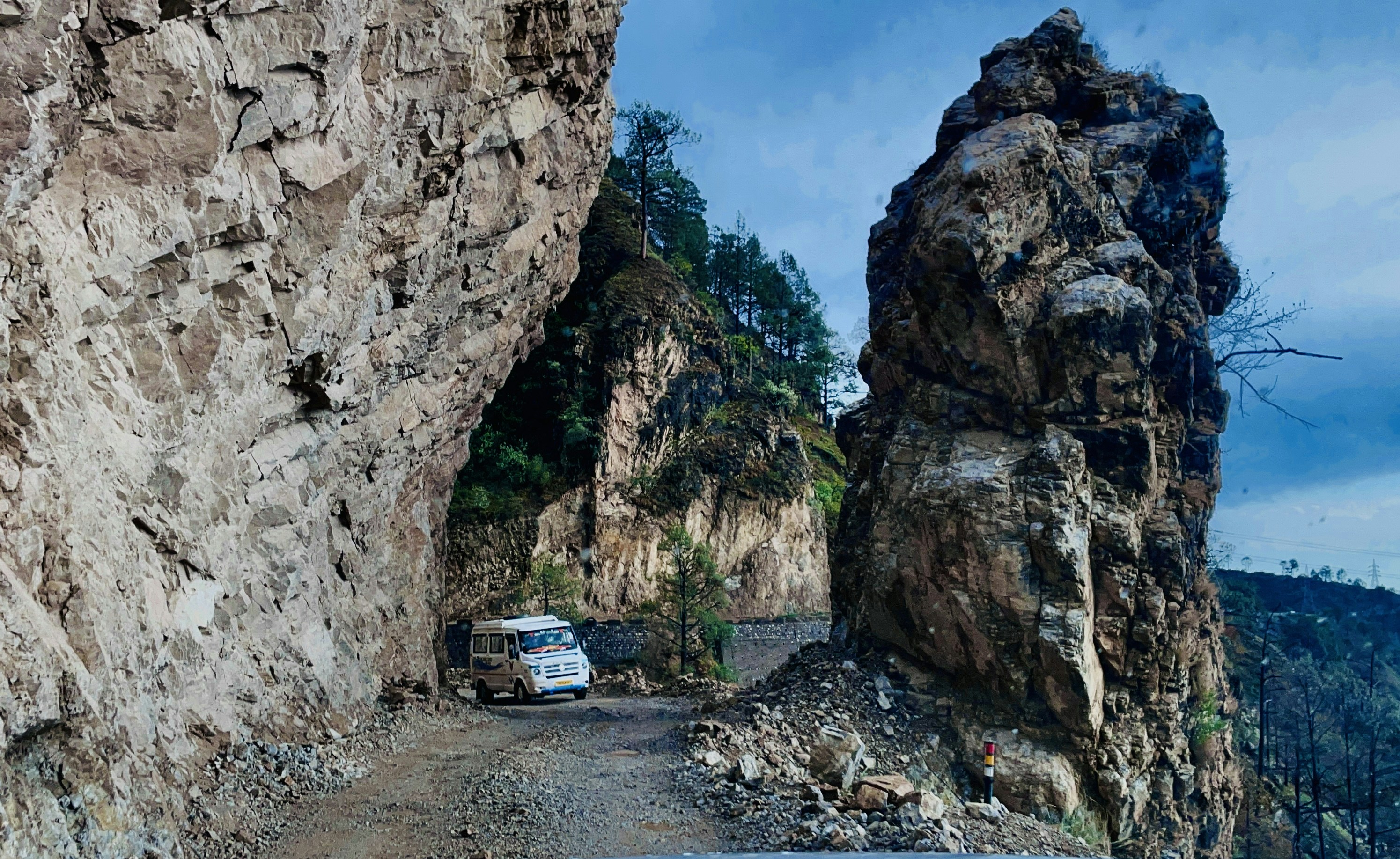 White Van Ventures Through a Cliffside Gorge Between Twin Granite Monoliths