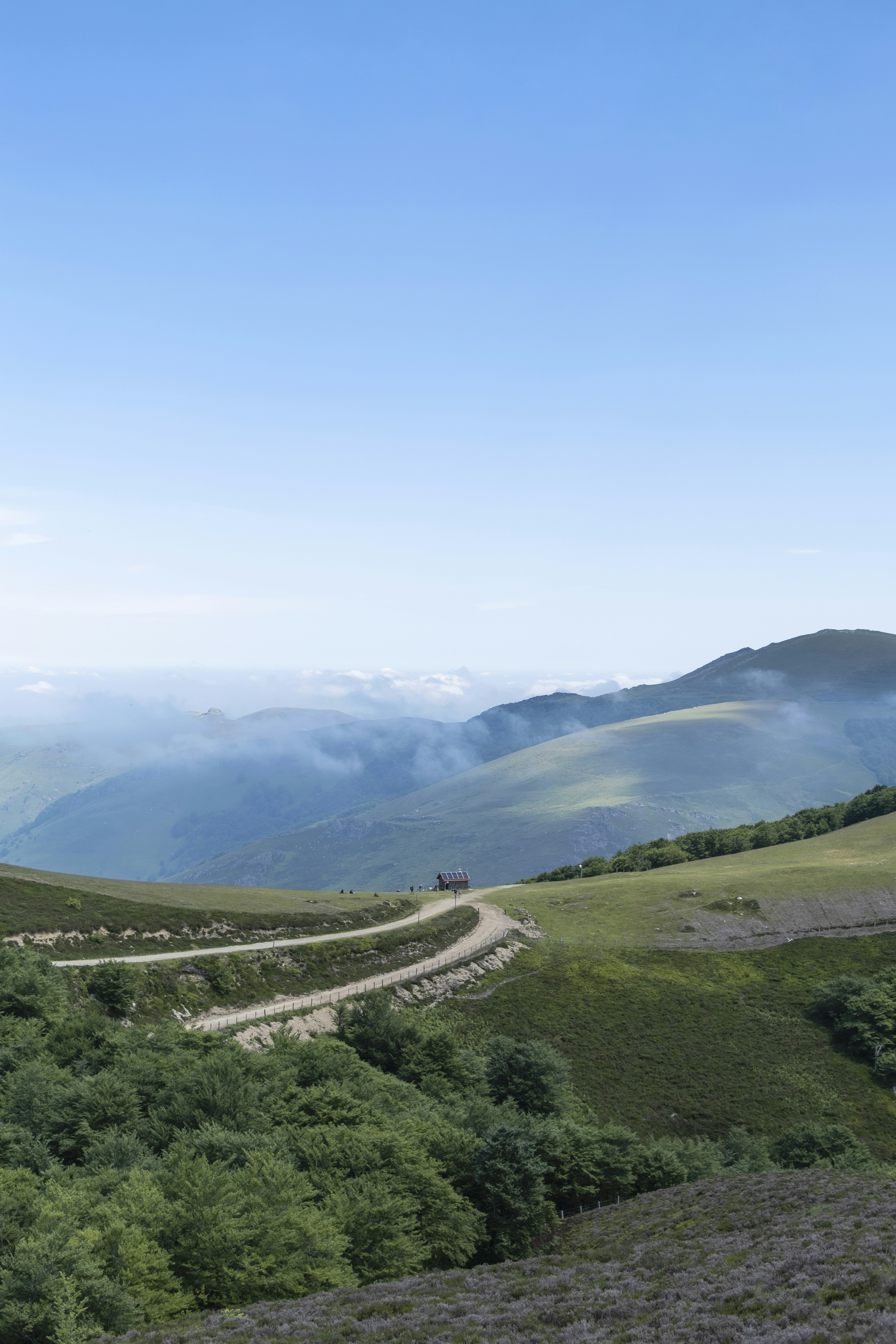 Winding Highland Spur: A Lonely Cabin Along Verdant Ridges Beneath a Clear Sky