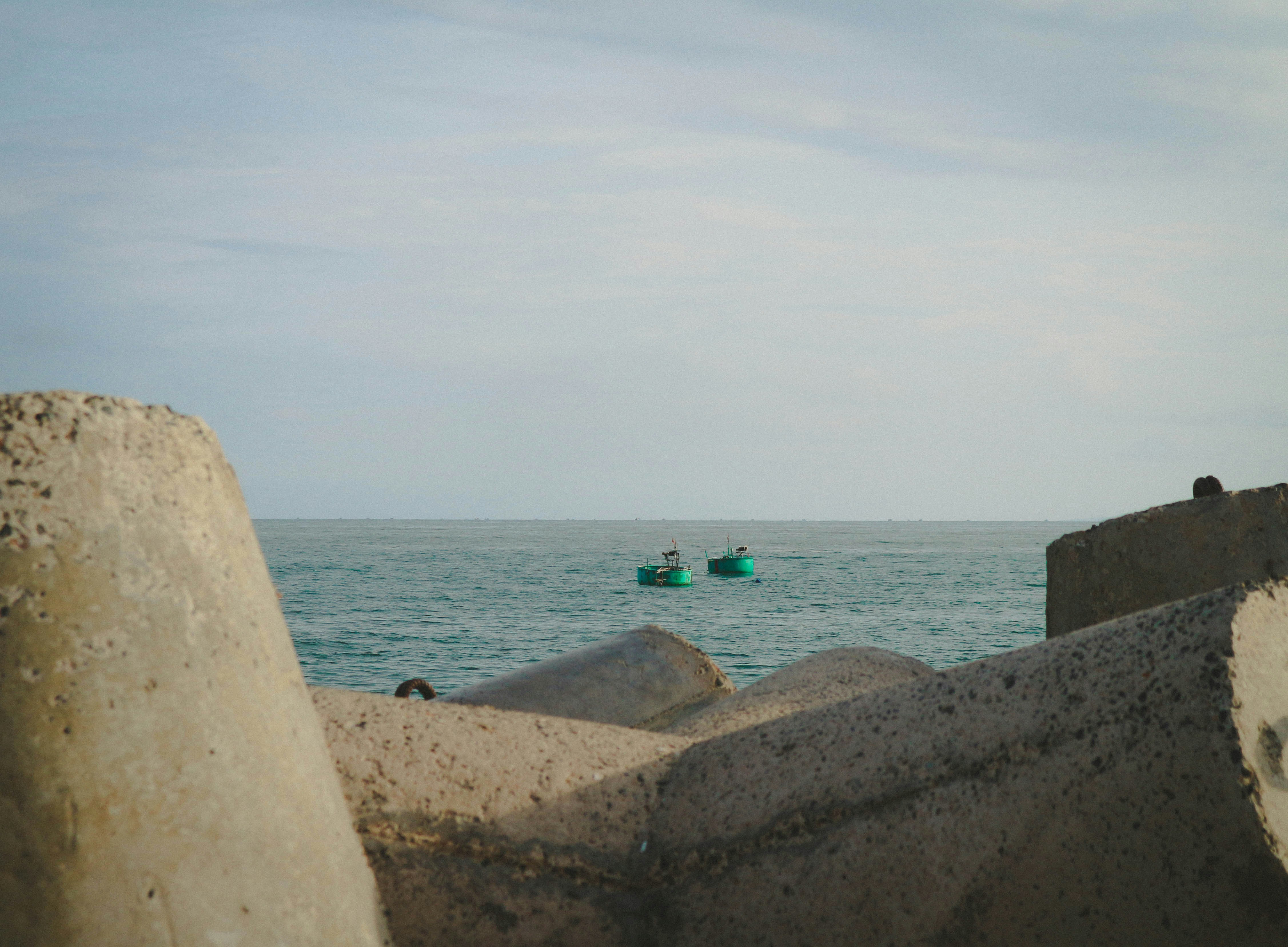 Emerald Dories on a Quiet Horizon Behind Weathered Breakwaters