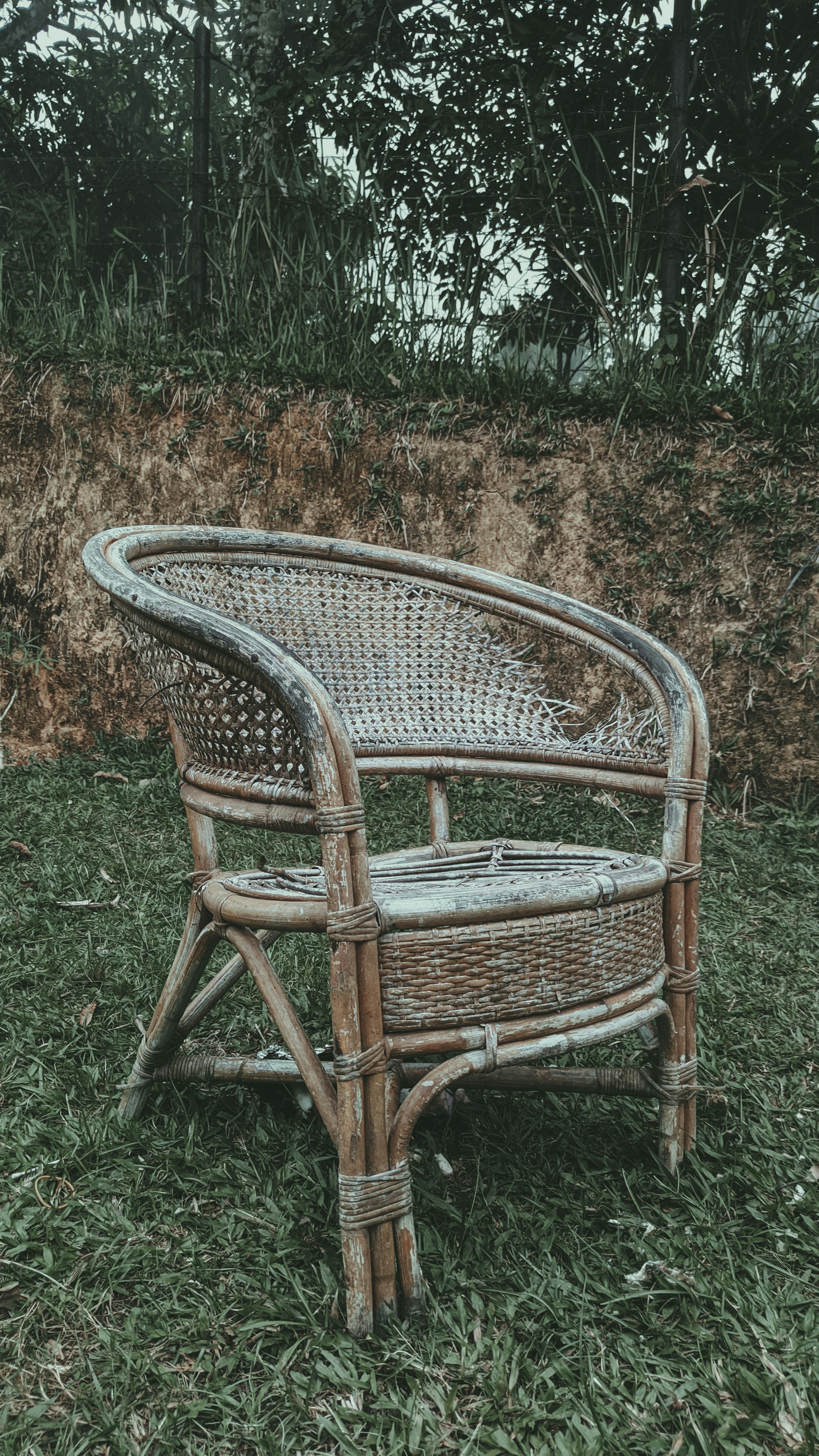 A vintage wicker chair nestled against a grassy backdrop, radiating a sense of tranquility and inviting relaxation.
