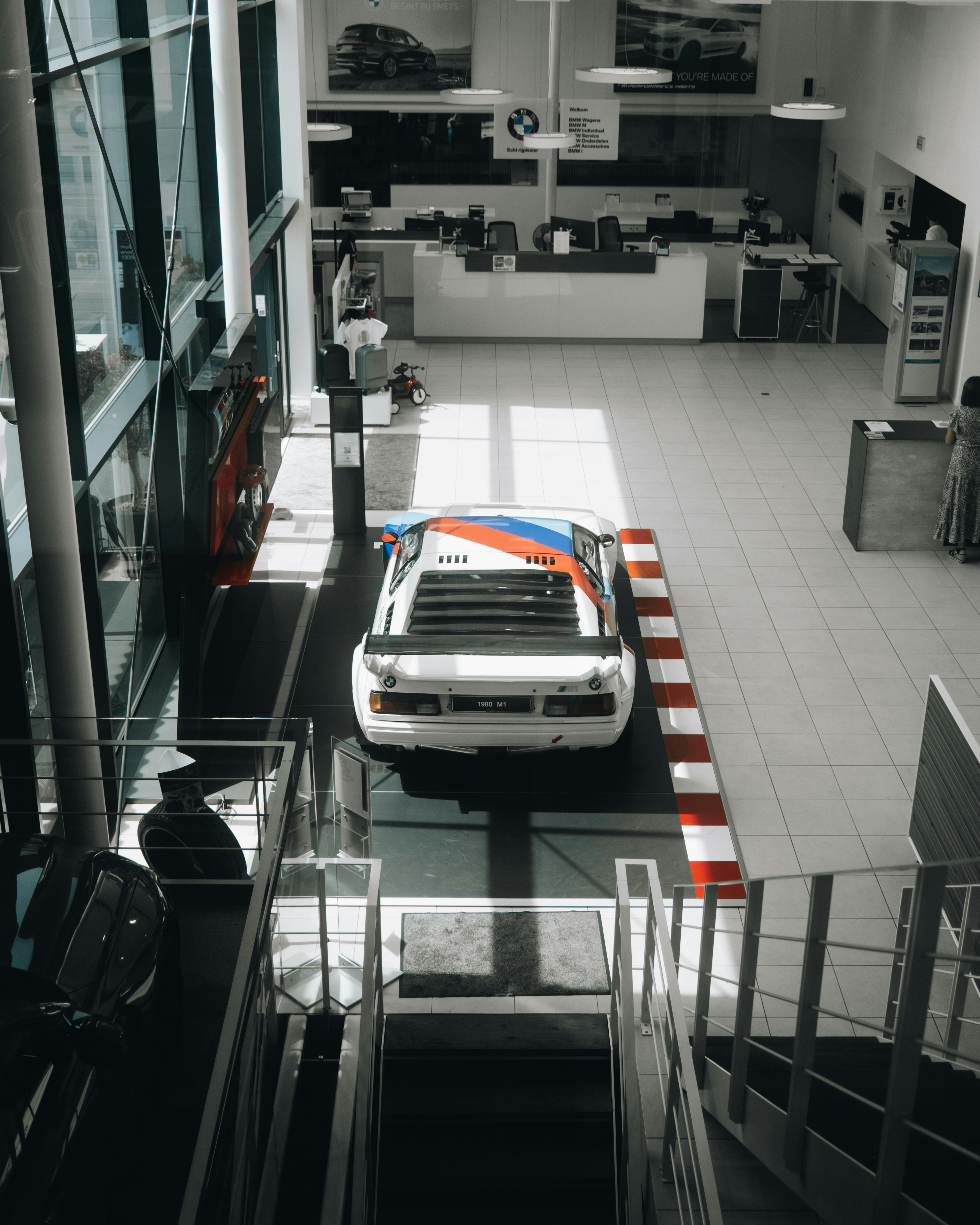Center-Stage Gulf Livery: A Sports Car Anchors a Sunlit Showroom
