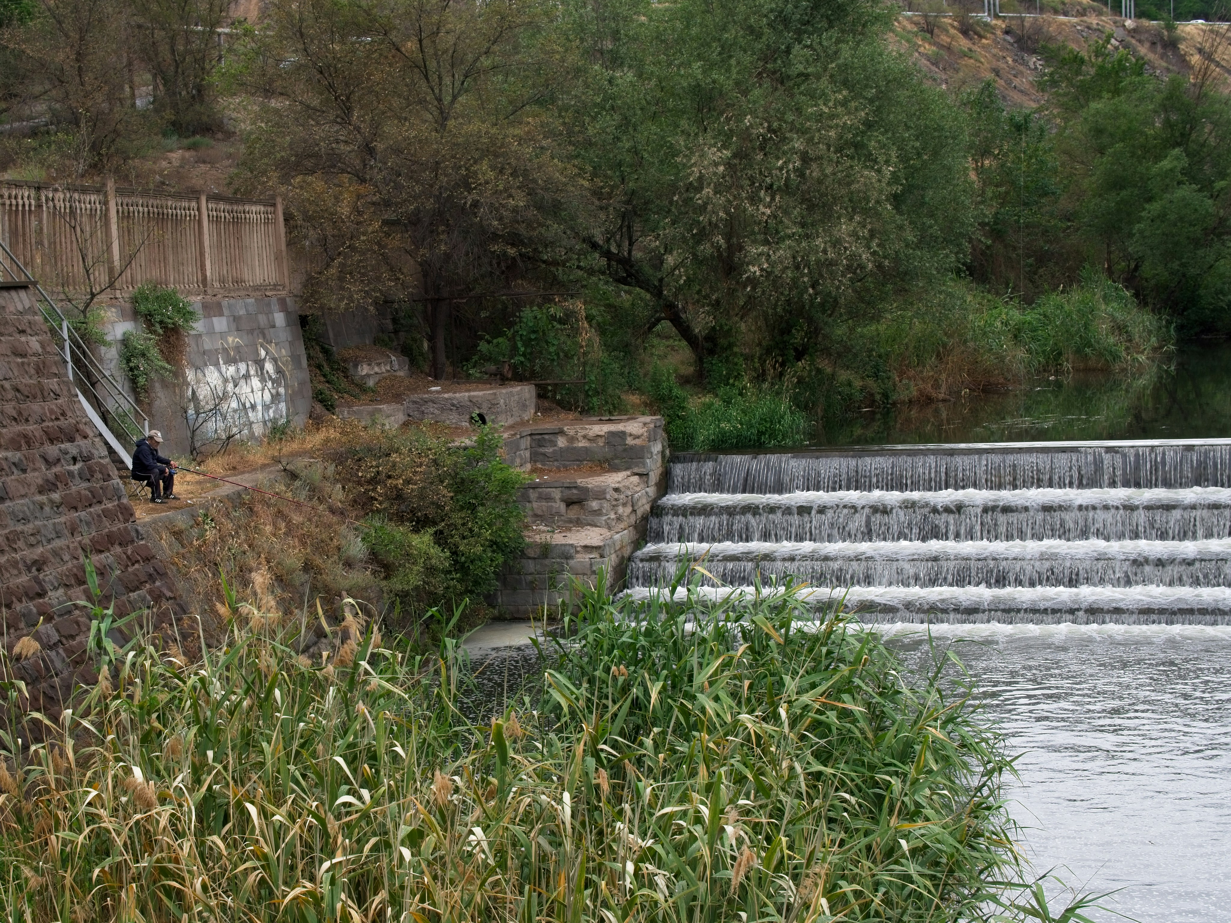 A person sitting on a bench next to a river photo – Free Nature Image ...