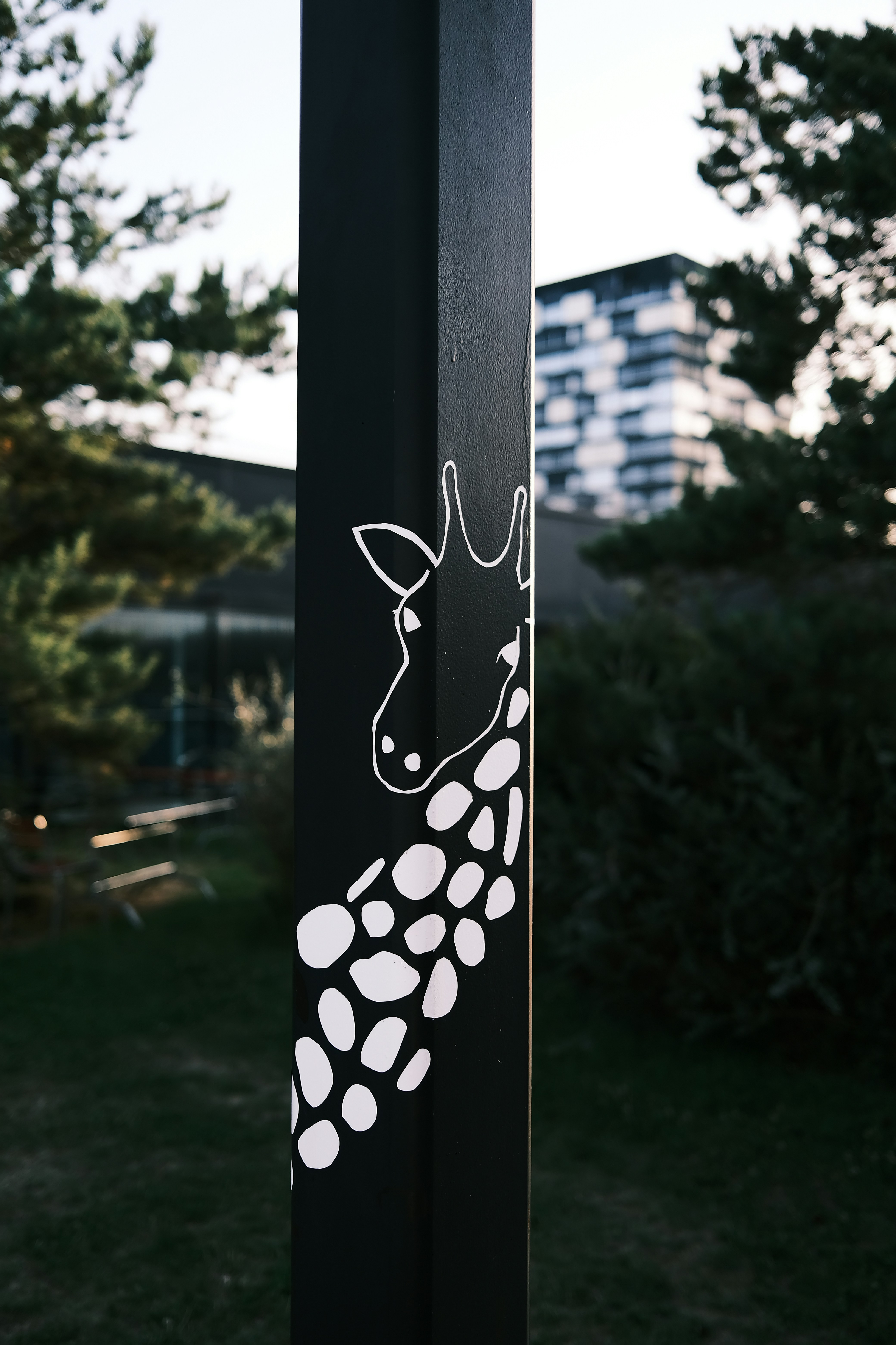 Giraffe Graffiti on a Vertical Pillar in a Quiet Campus Courtyard