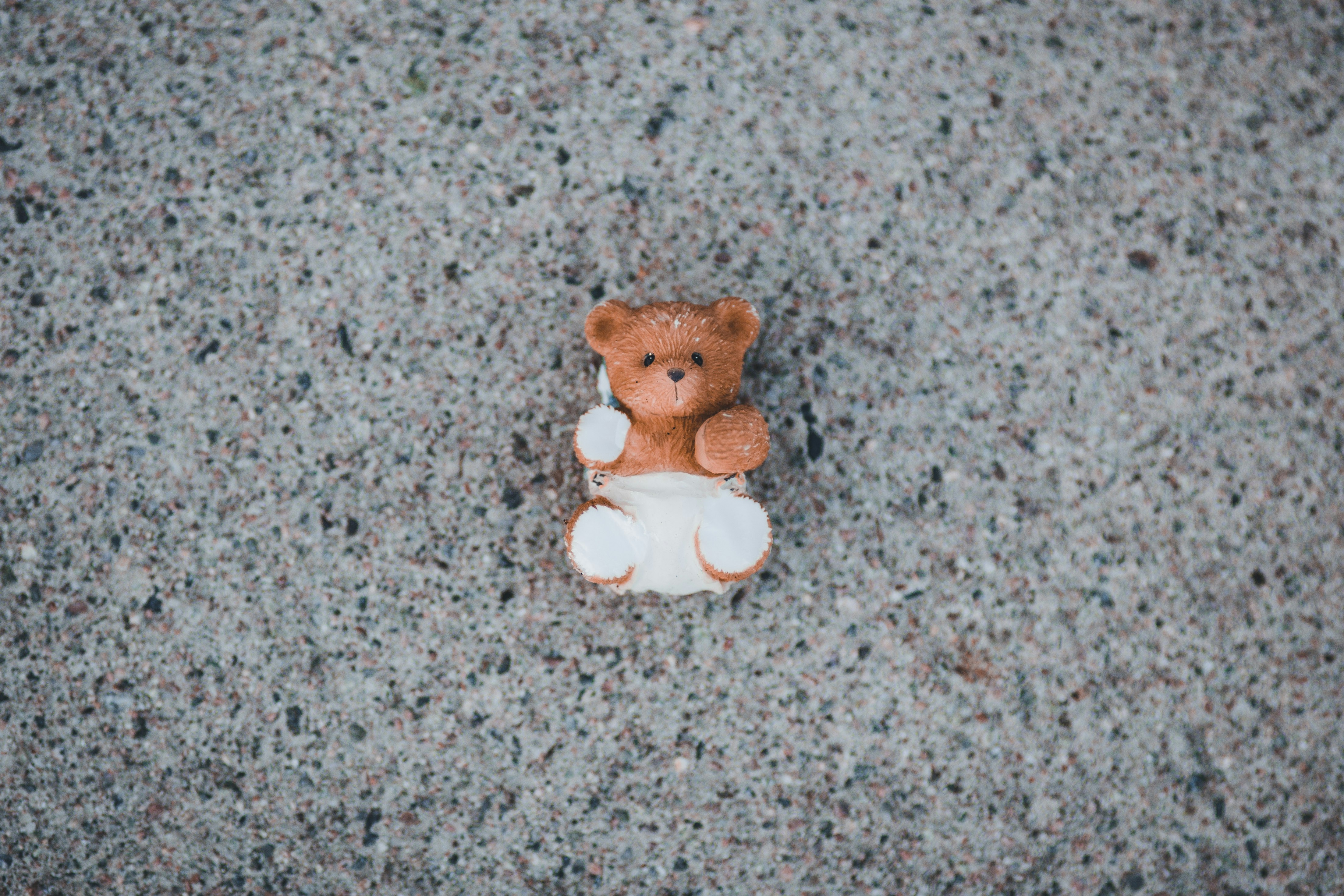 Tiny Bear on a Grainy Stage: A Quiet Toy in Concrete Textures
