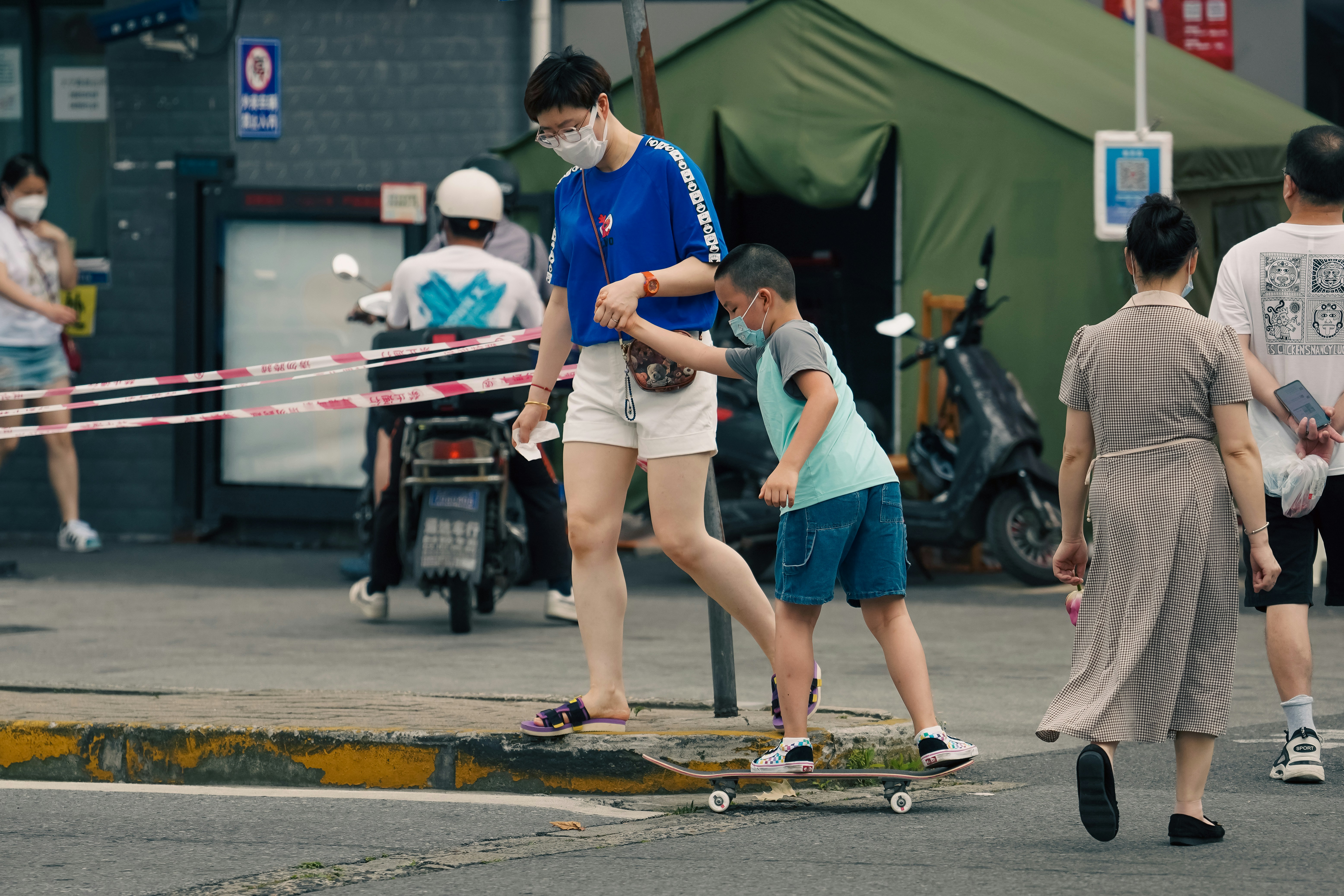 a person riding a skateboard with a kid on a scooter