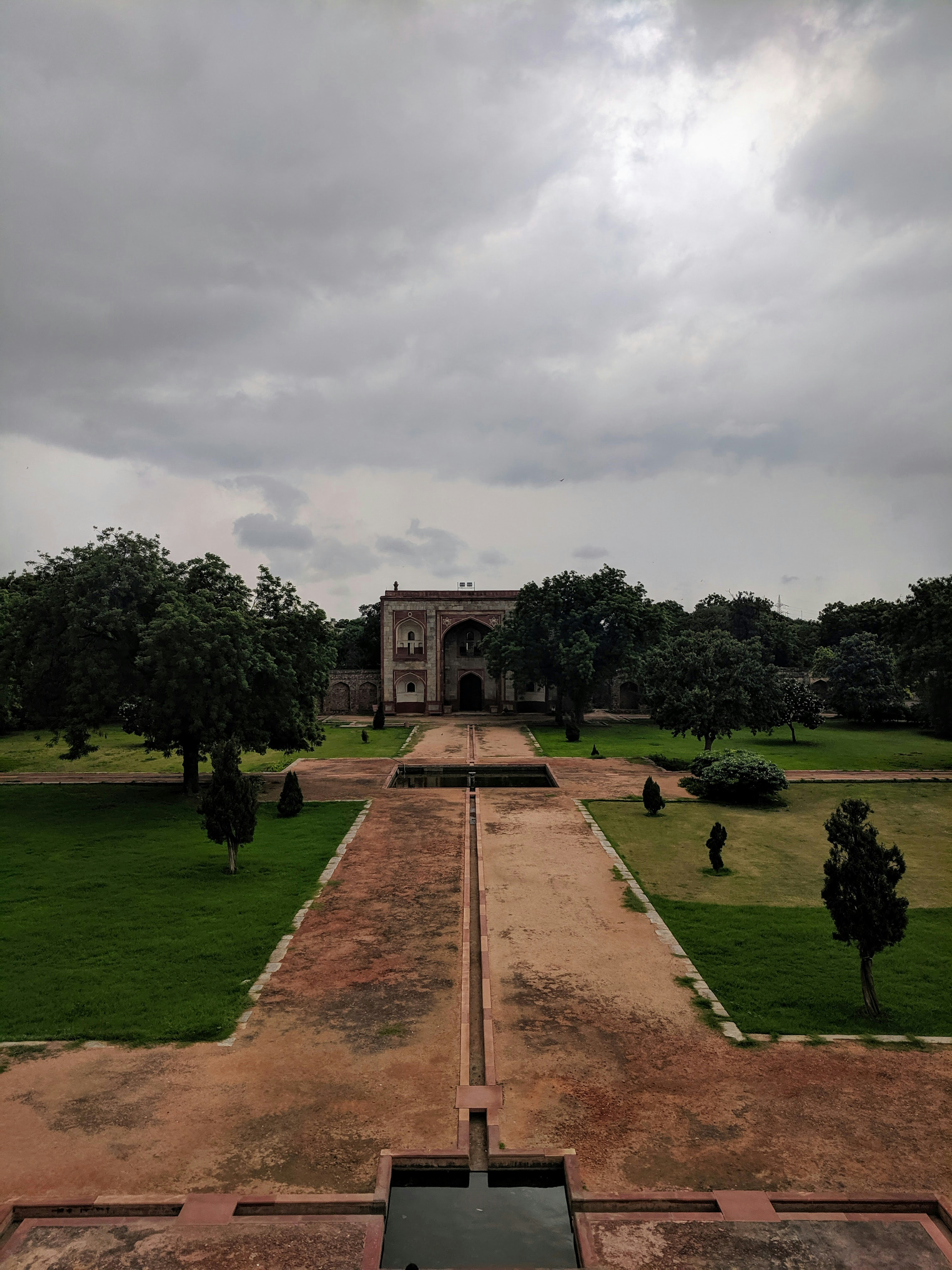 a large stone building with a large lawn and trees in front of it