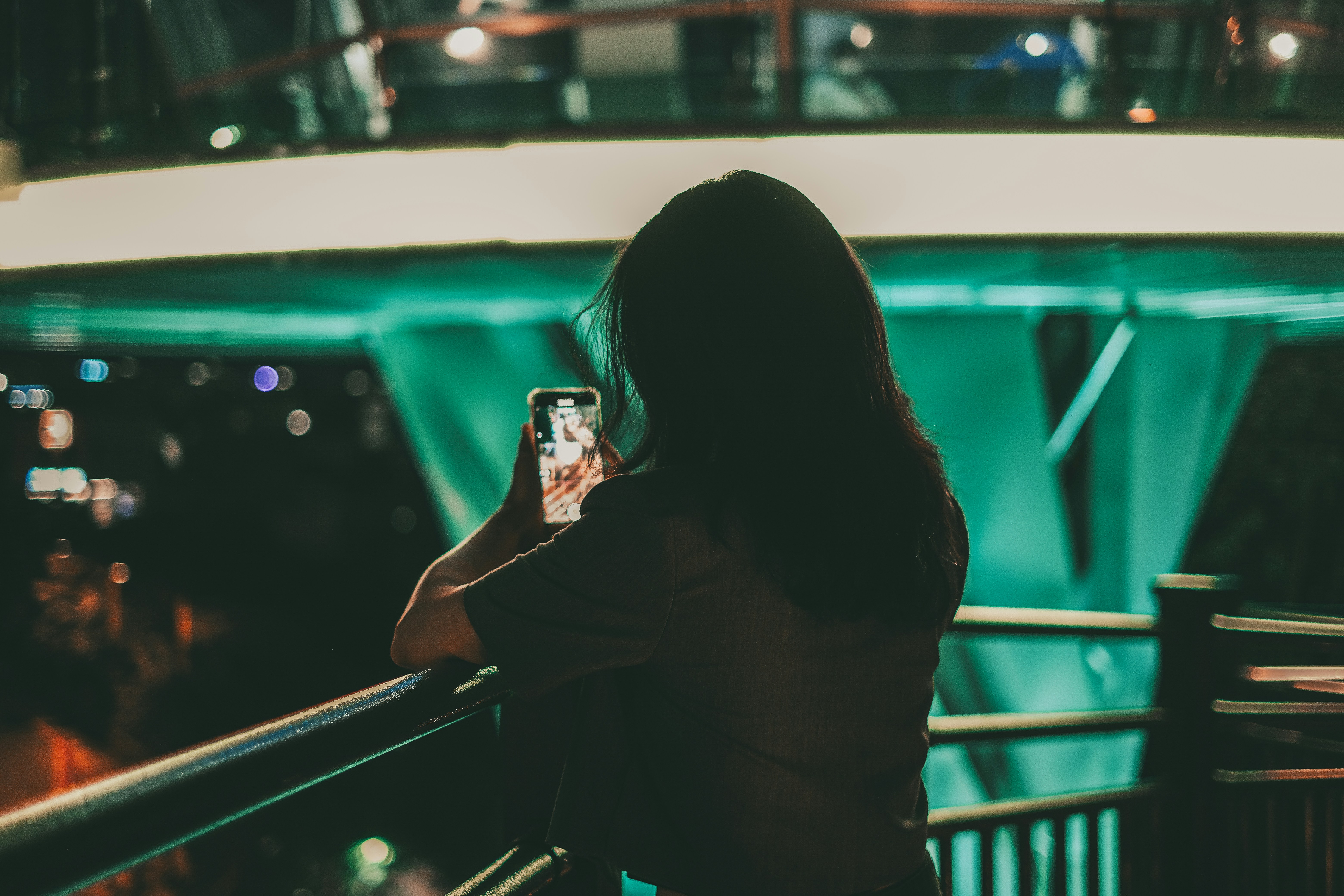 Silhouette of a person taking a photo against a backdrop of vibrant neon lights in an urban setting.