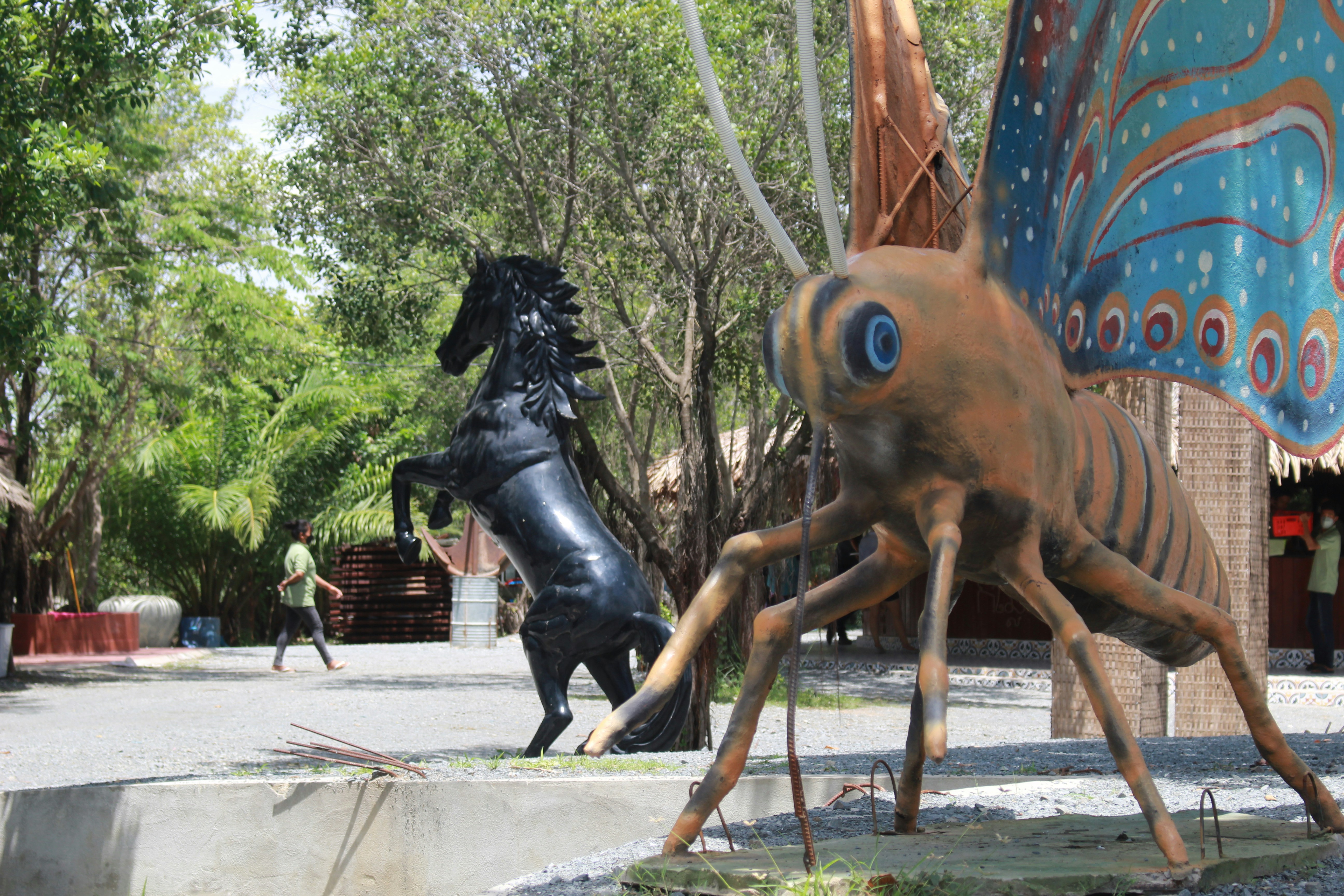 Quiet Park Duel: A Black Metal Stallion confronts a colossal orange butterfly sculpture