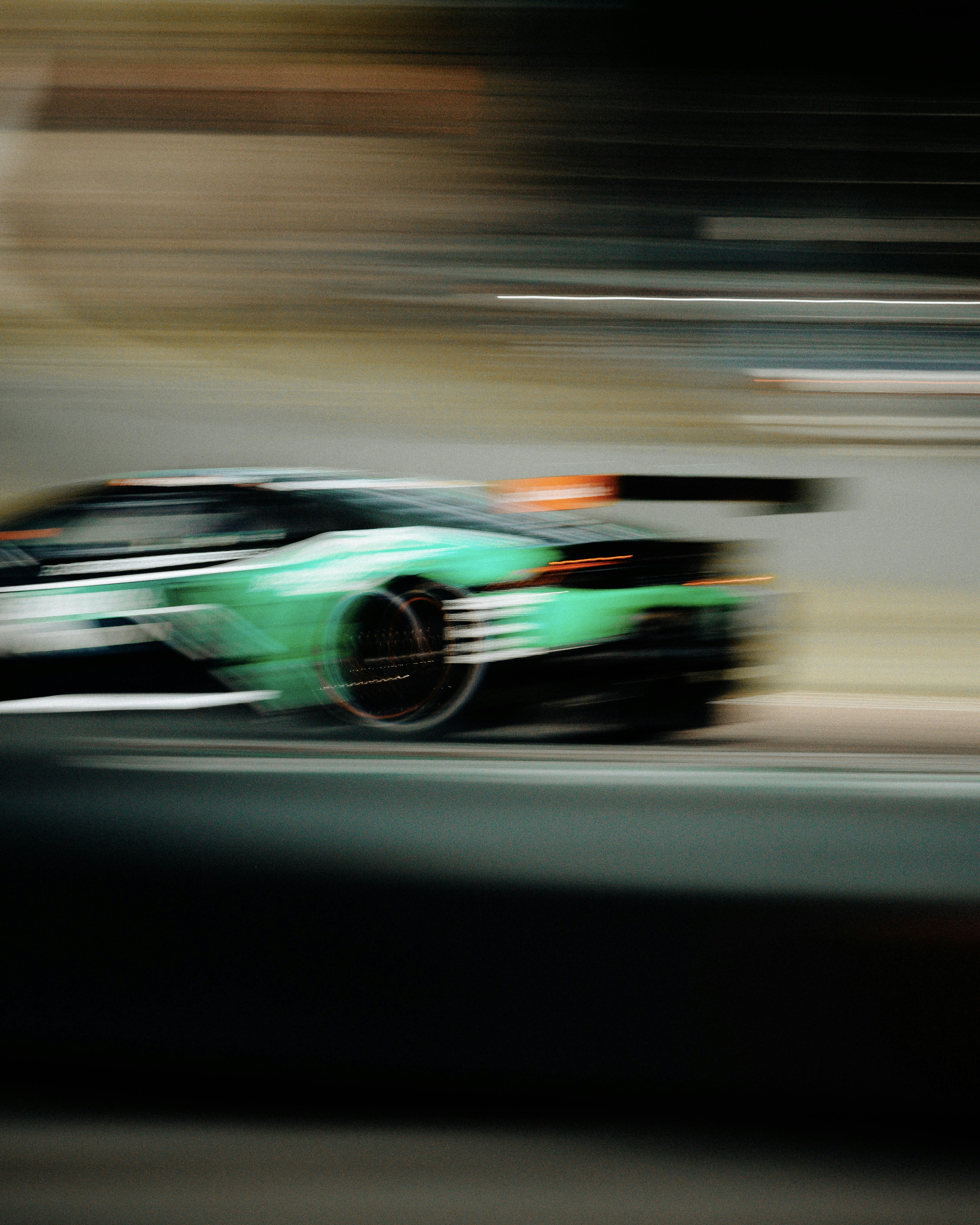 A high-speed racing car blurs past the camera, showcasing its sleek design and dynamic movement on the track.