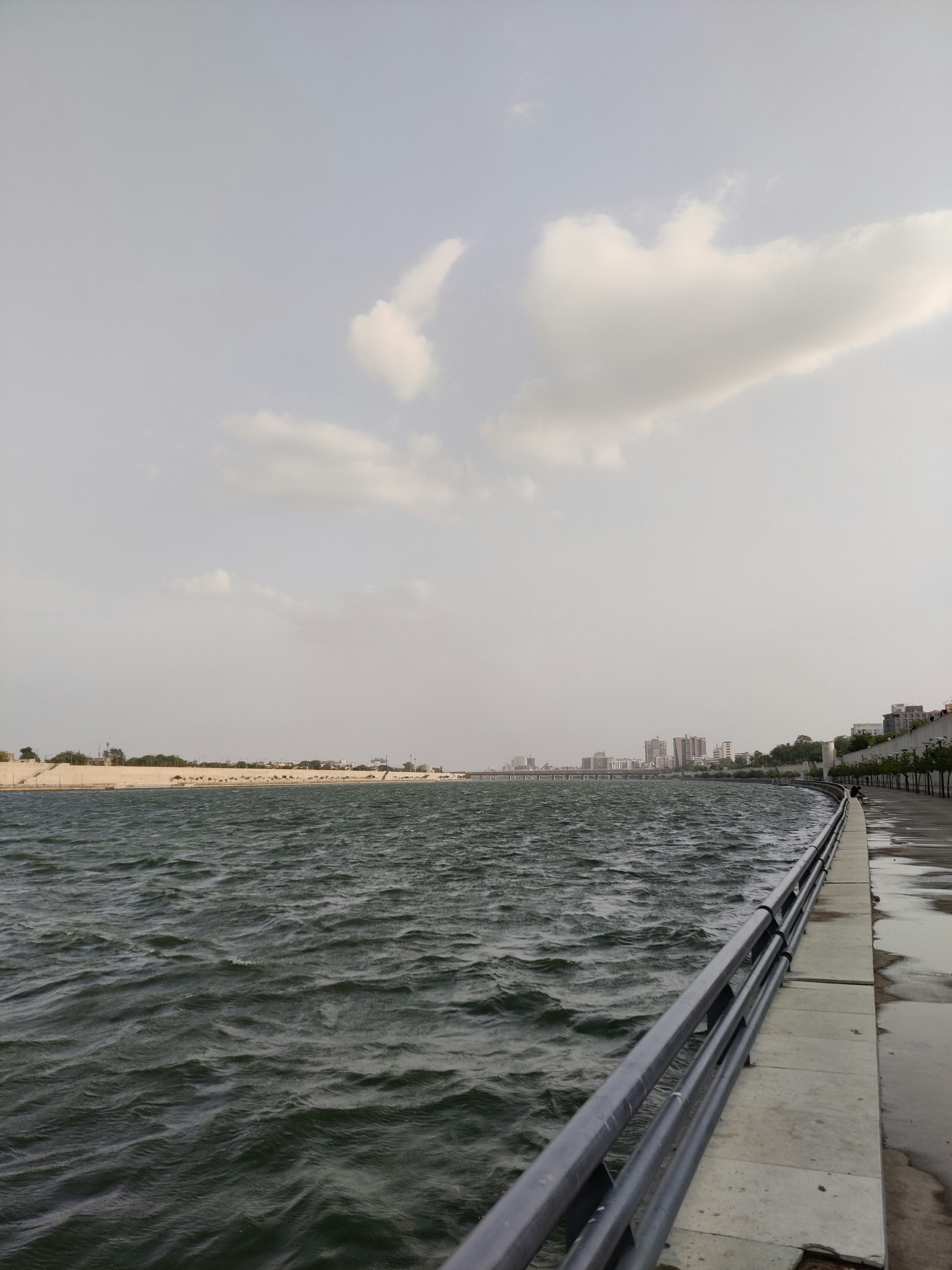 a body of water with a walkway and a city in the background