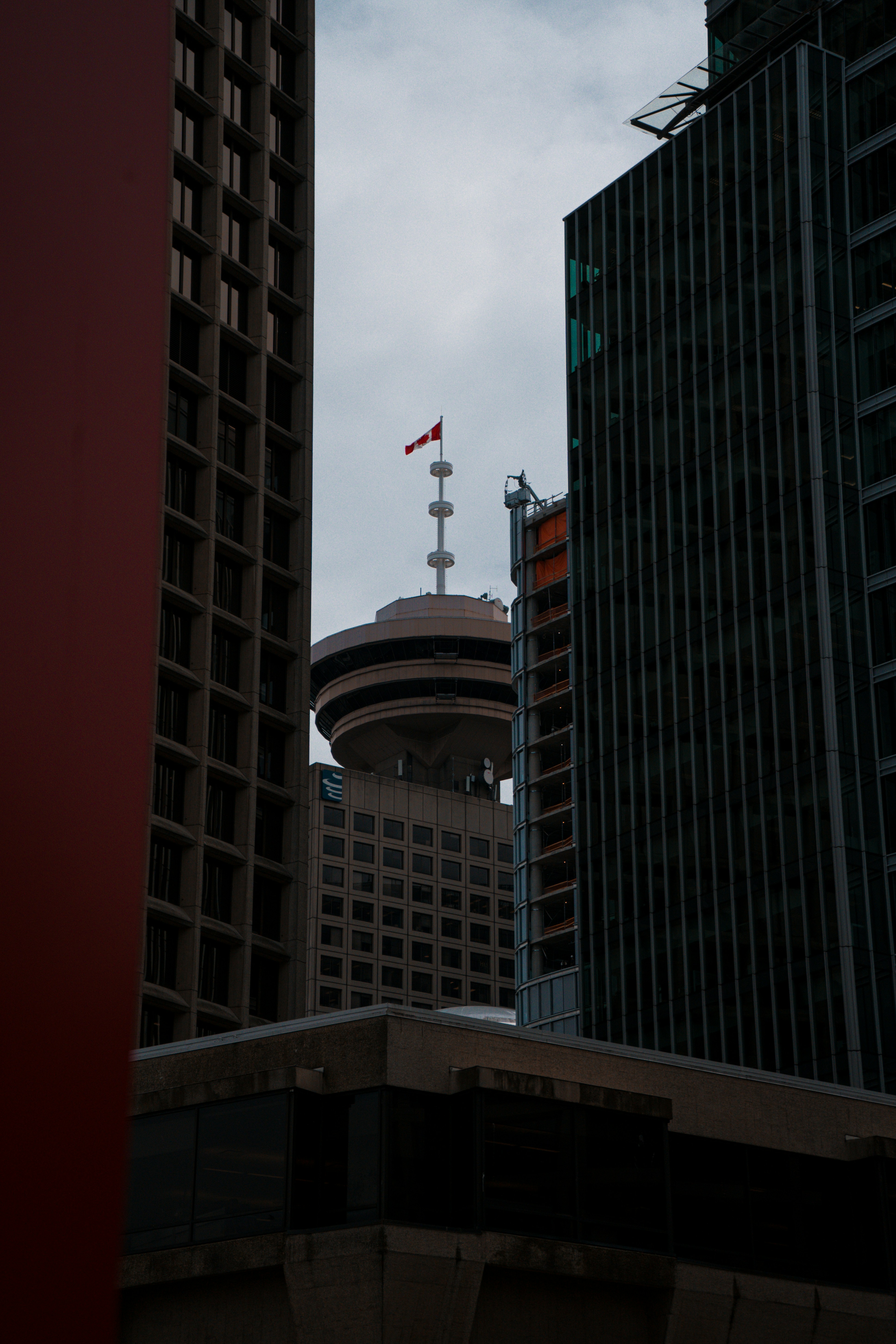 The iconic tower with a Canadian flag peeks through a maze of modern skyscrapers, showcasing the blend of urban architecture. 