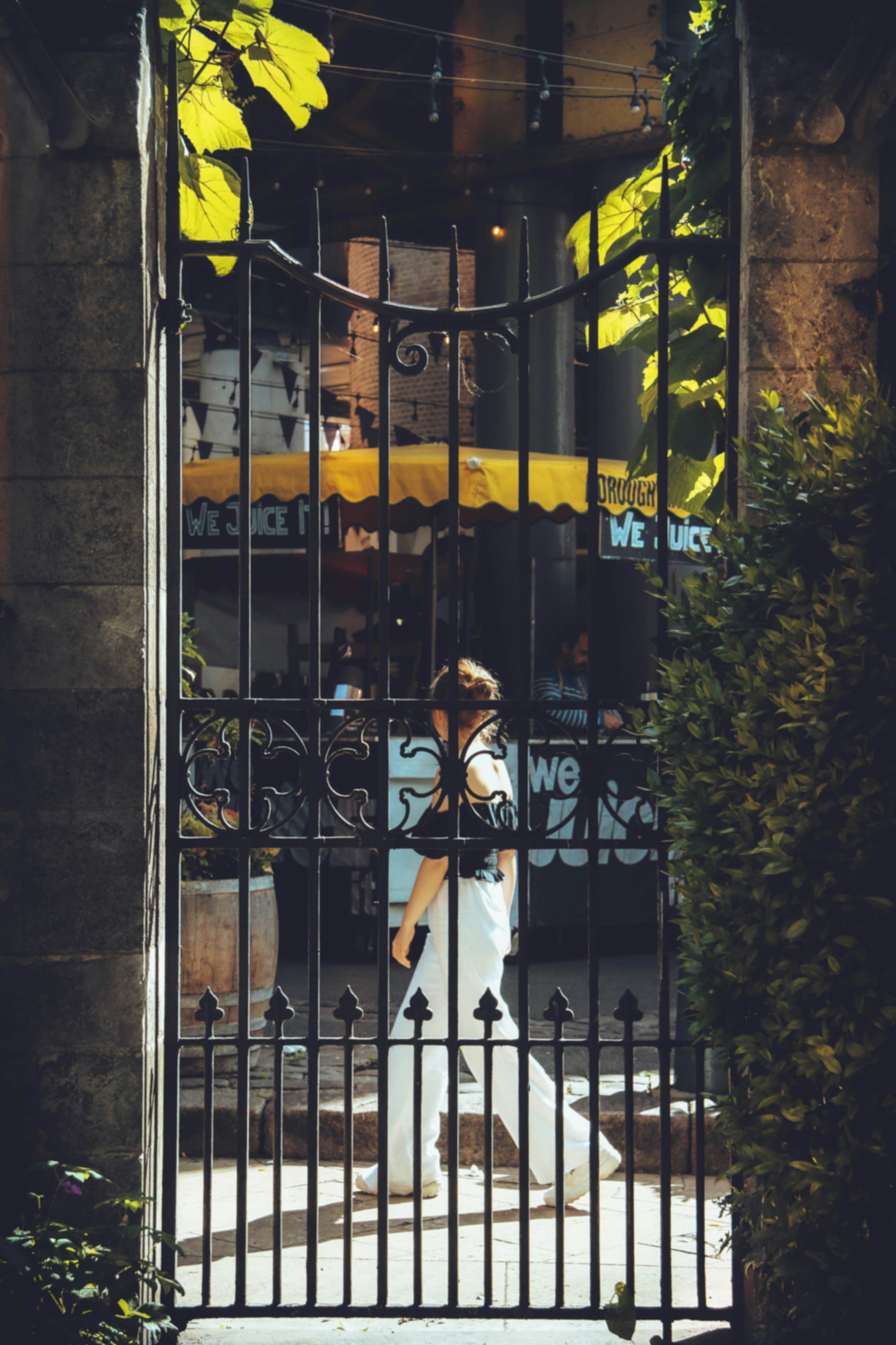 Through the Gate: A Quiet Walk Toward a Sunlit Café Terrace