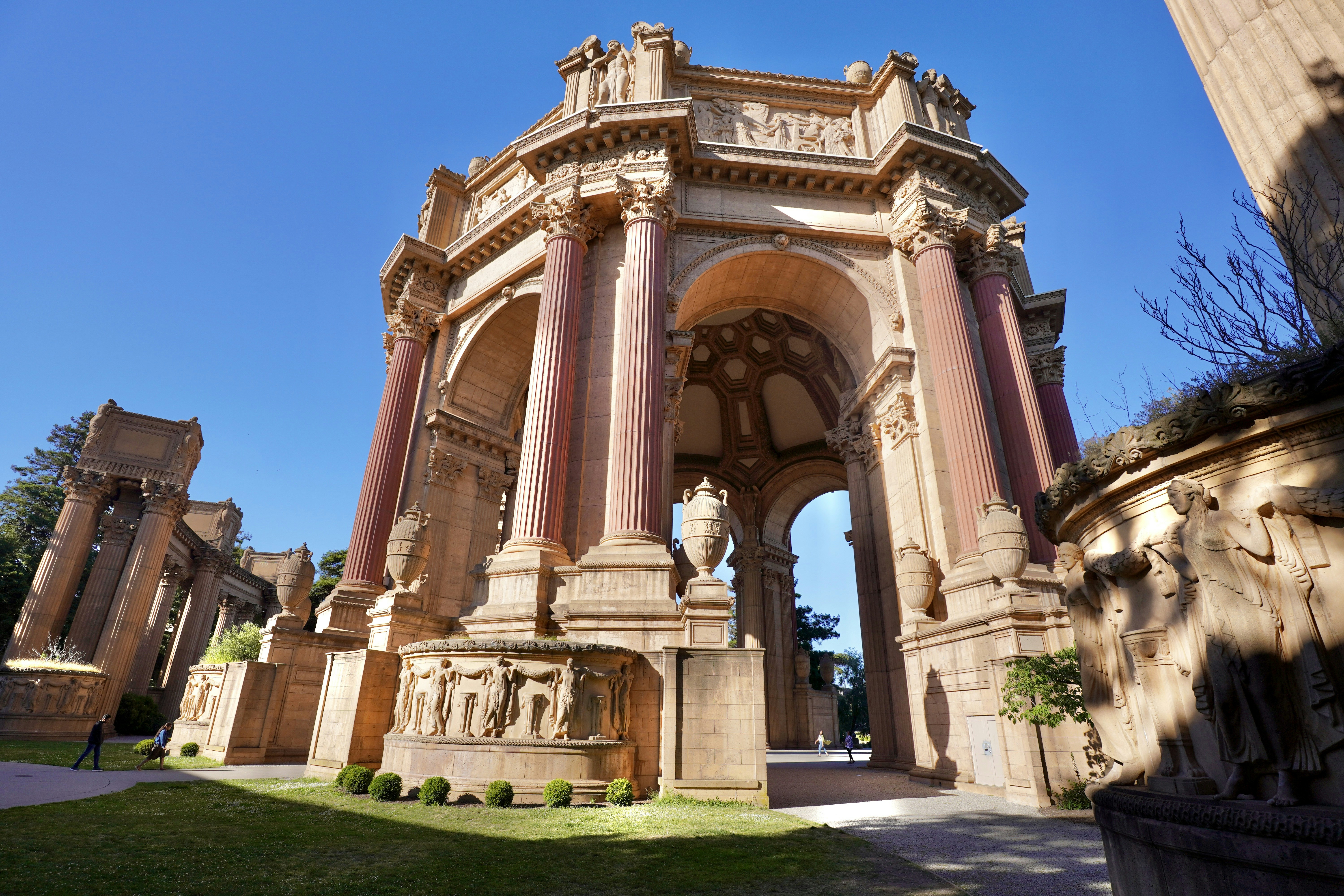 Sunlit Grandeur: A Classical Arch Framed by Crimson Columns