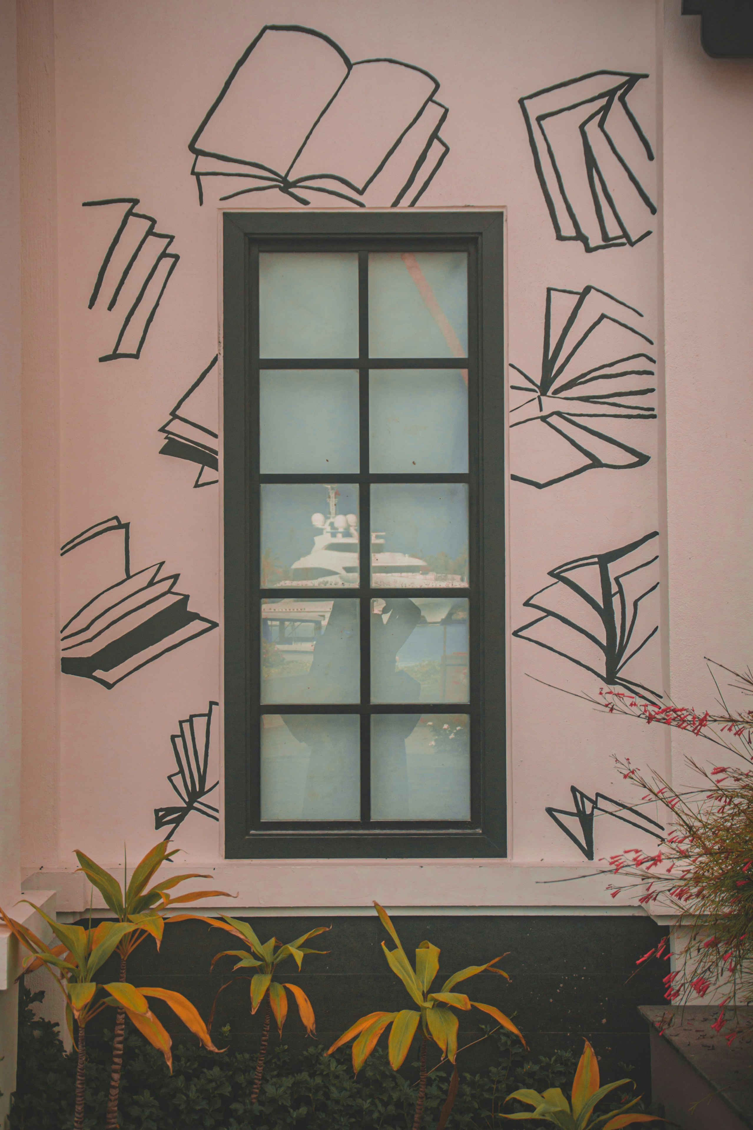 Framed Tomes: A Window Surrounded by Bookish Wall Art on a Pink Facade