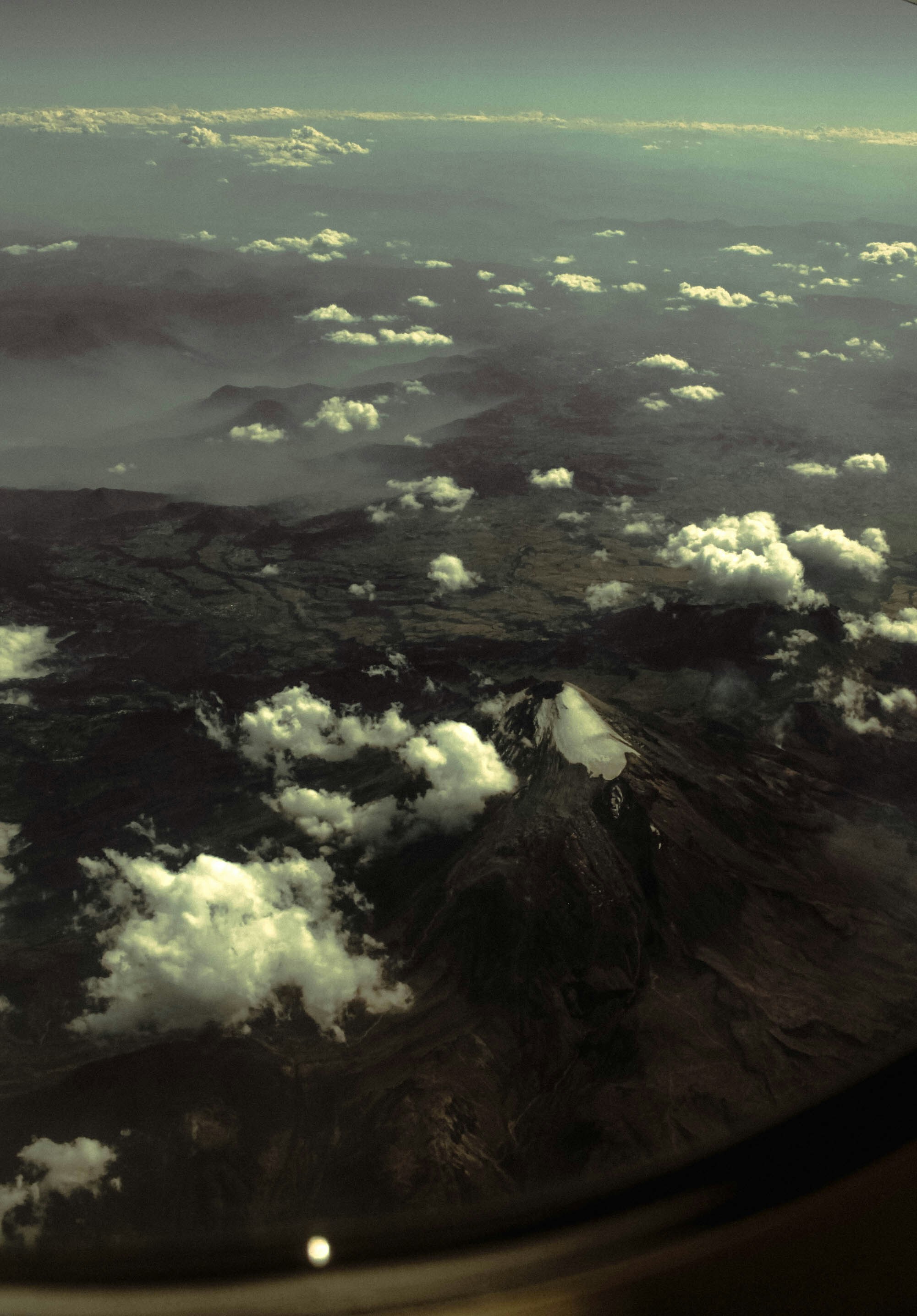 Aerial Vista: Snow-Crowned Peak Emerging Through a Patchwork of Clouds