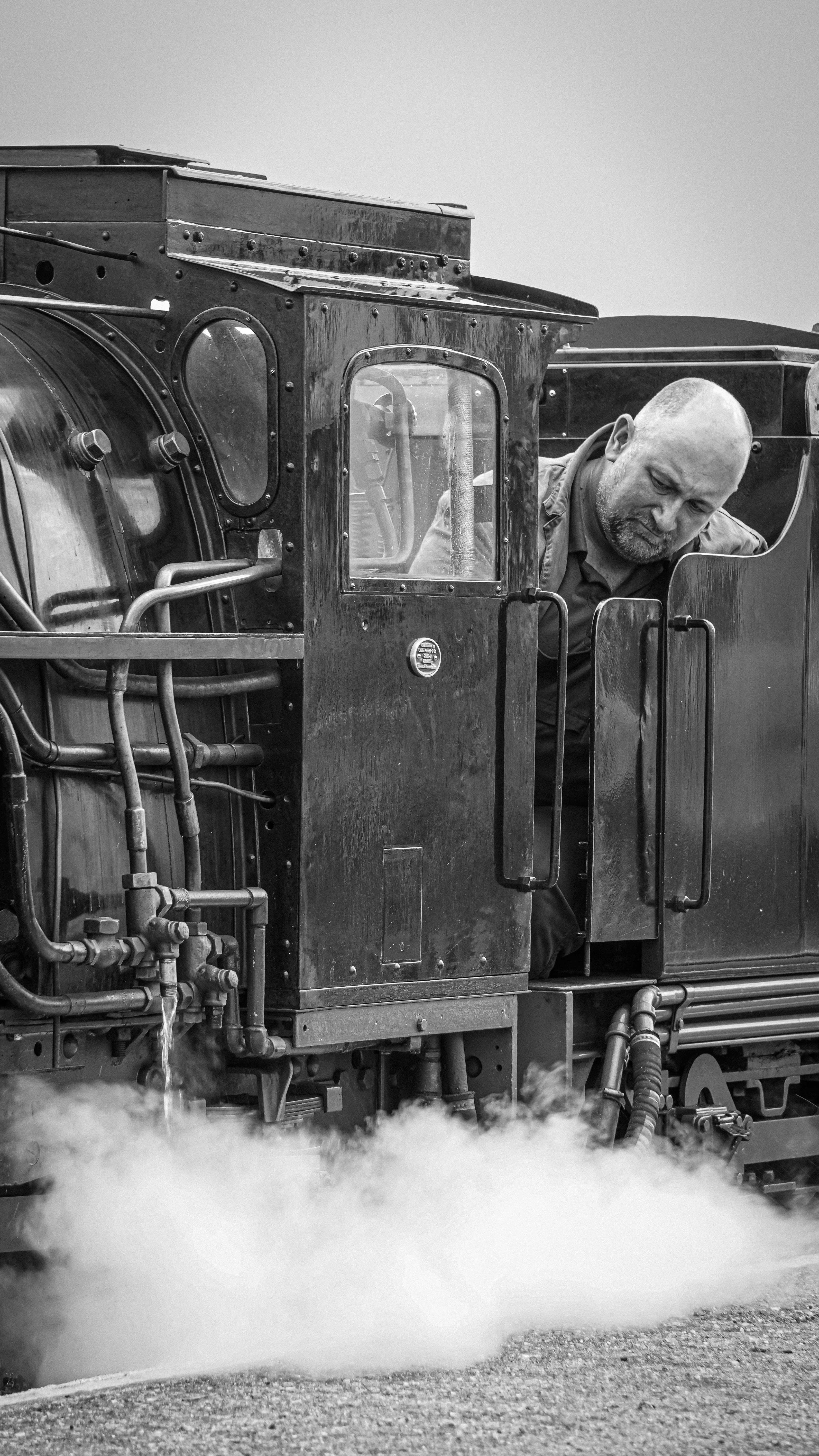 At the Cab Door: Focused Engineer Amid a Thundering Steam Locomotive