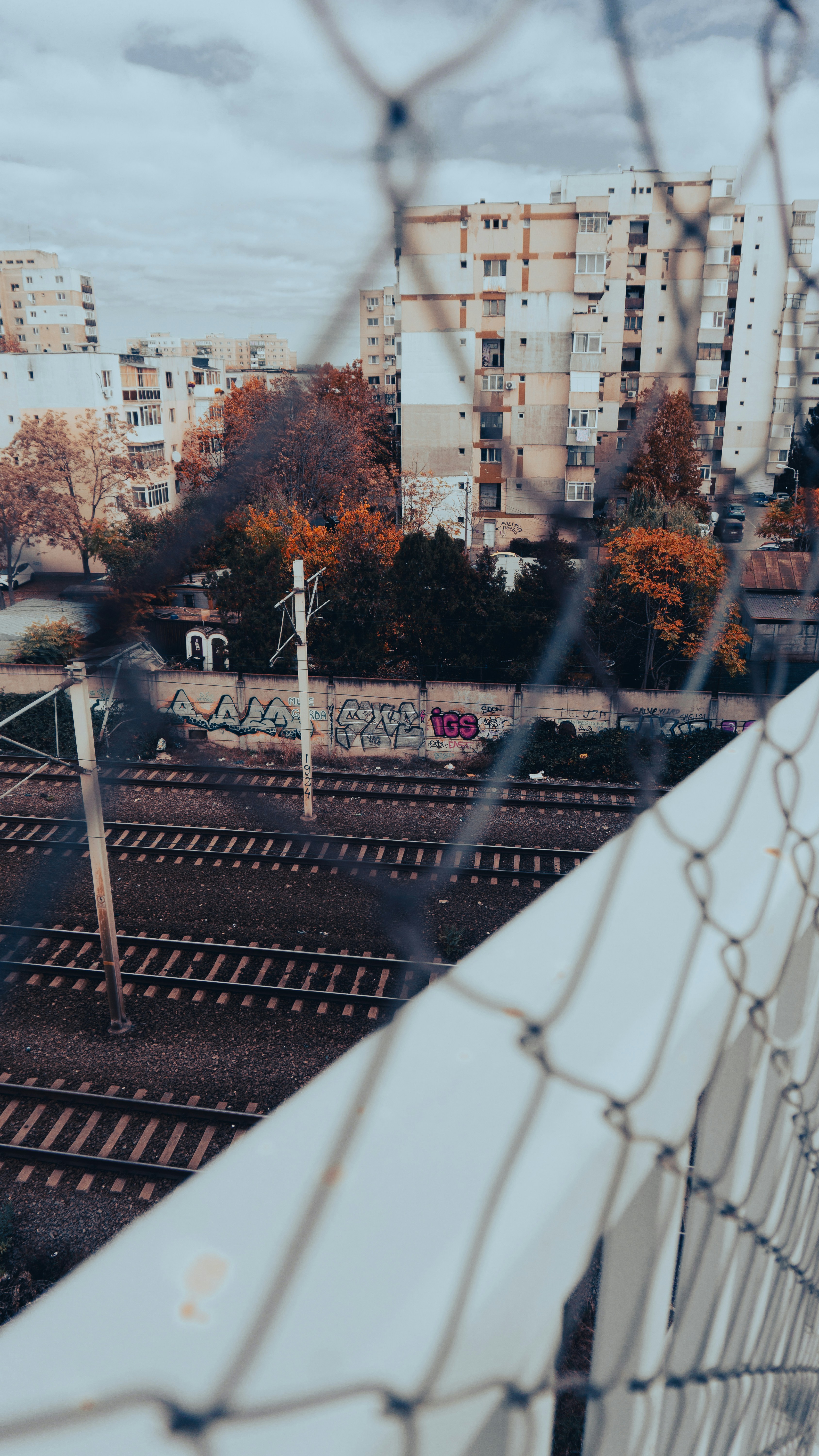 Between Rails and Skyline: An Autumn Cityscape Framed by Chain-Link