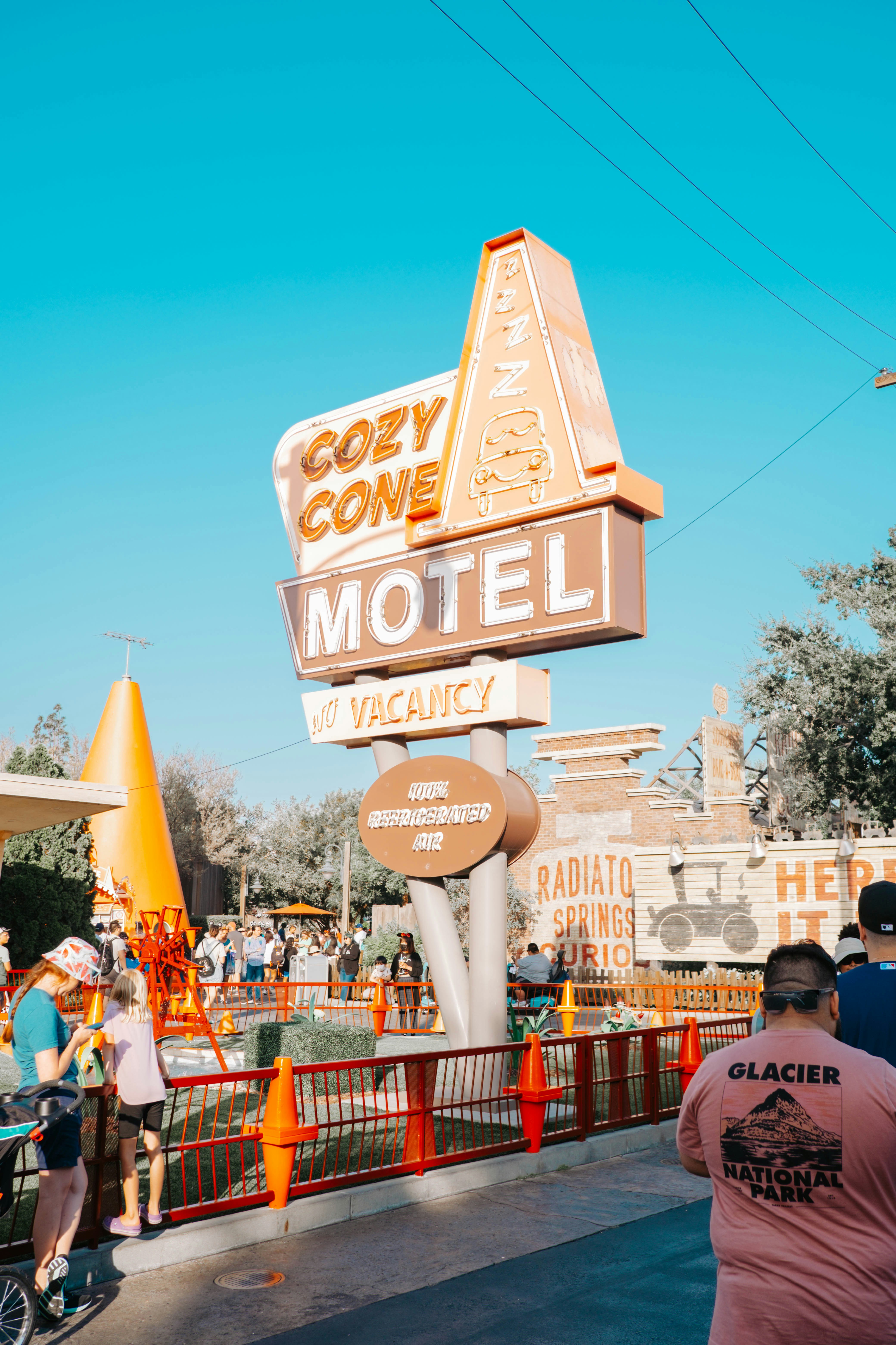 Vibrant sign of the Cozy Cone Motel, showcasing a playful design with a classic roadside aesthetic. Visitors enjoy the lively atmosphere in Radiator Springs.