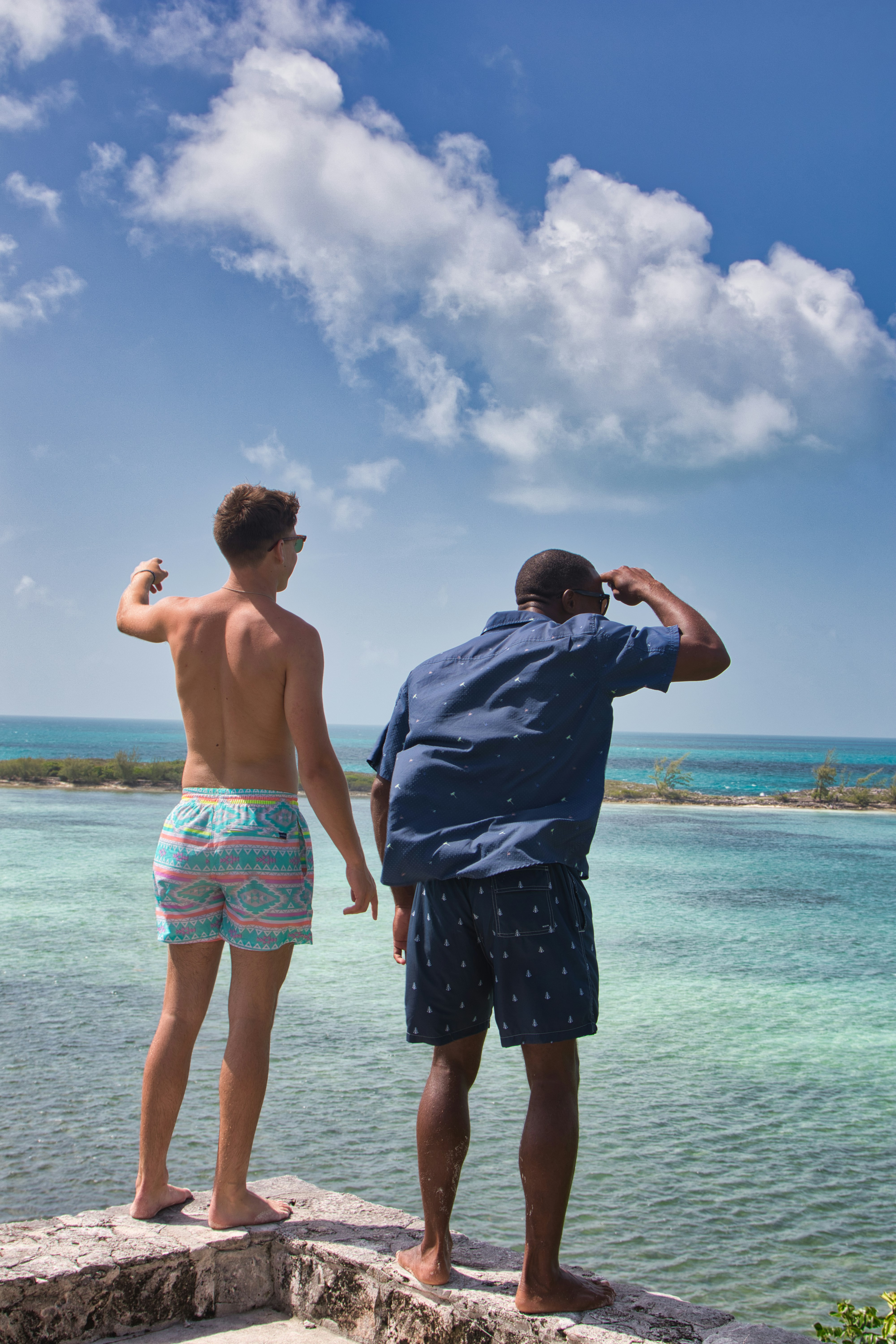 Coastal vantage: two friends scan the horizon from a sunlit jetty