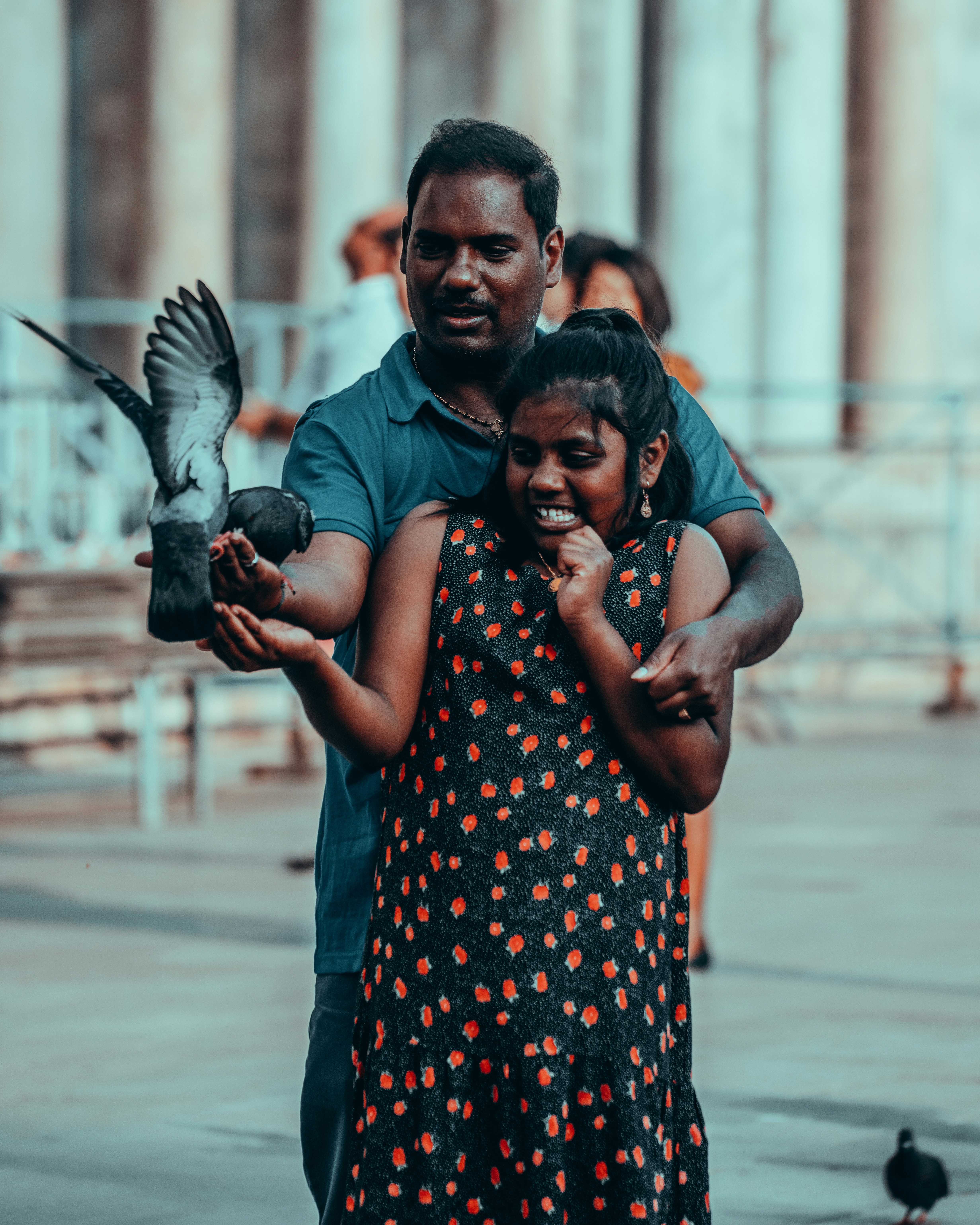 A Father and Daughter Share a Moment as a Pigeon Takes Flight