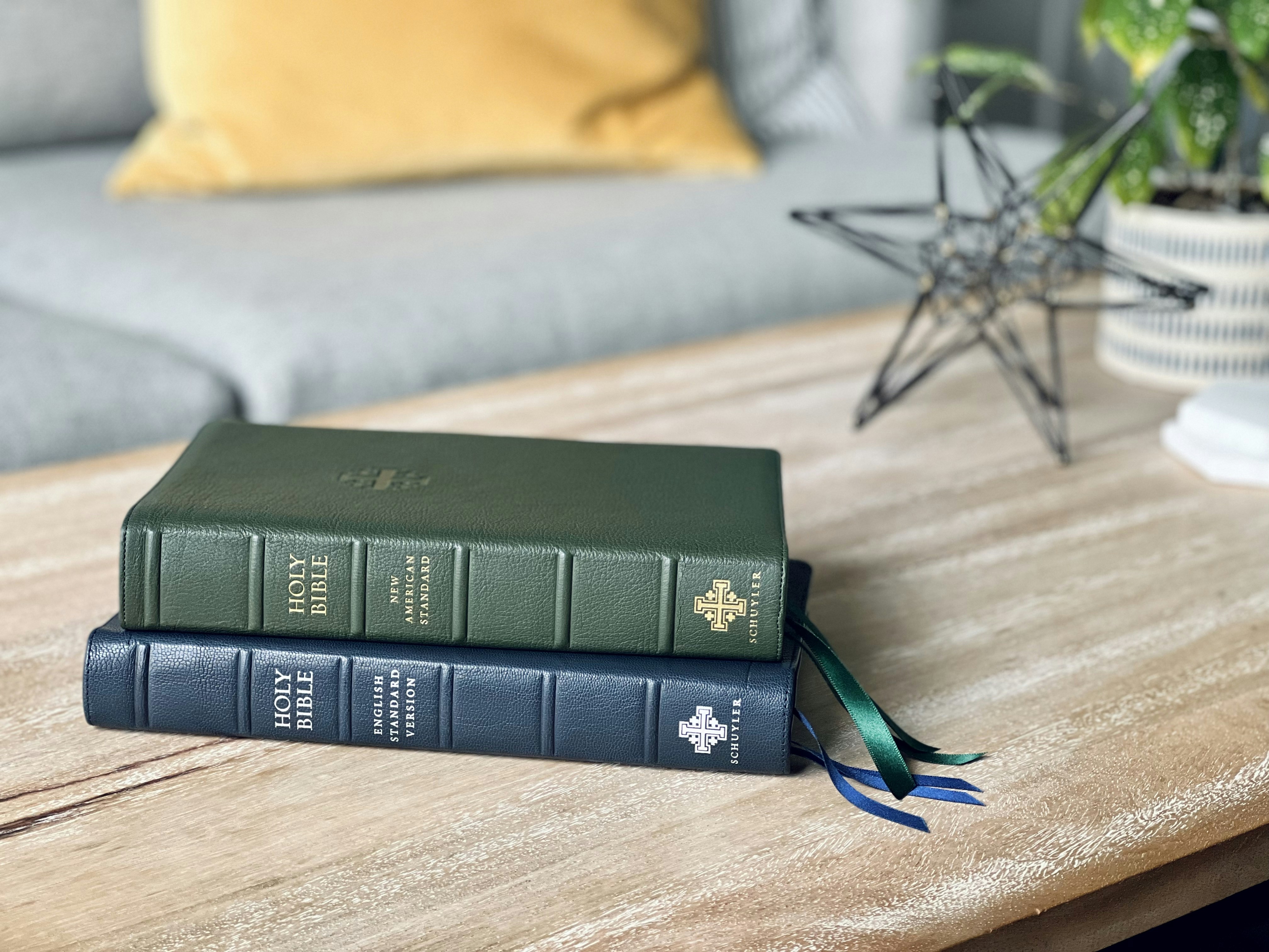 Two elegantly bound Bibles resting on a wooden table, accompanied by a decorative star and a potted plant in a cozy living space.