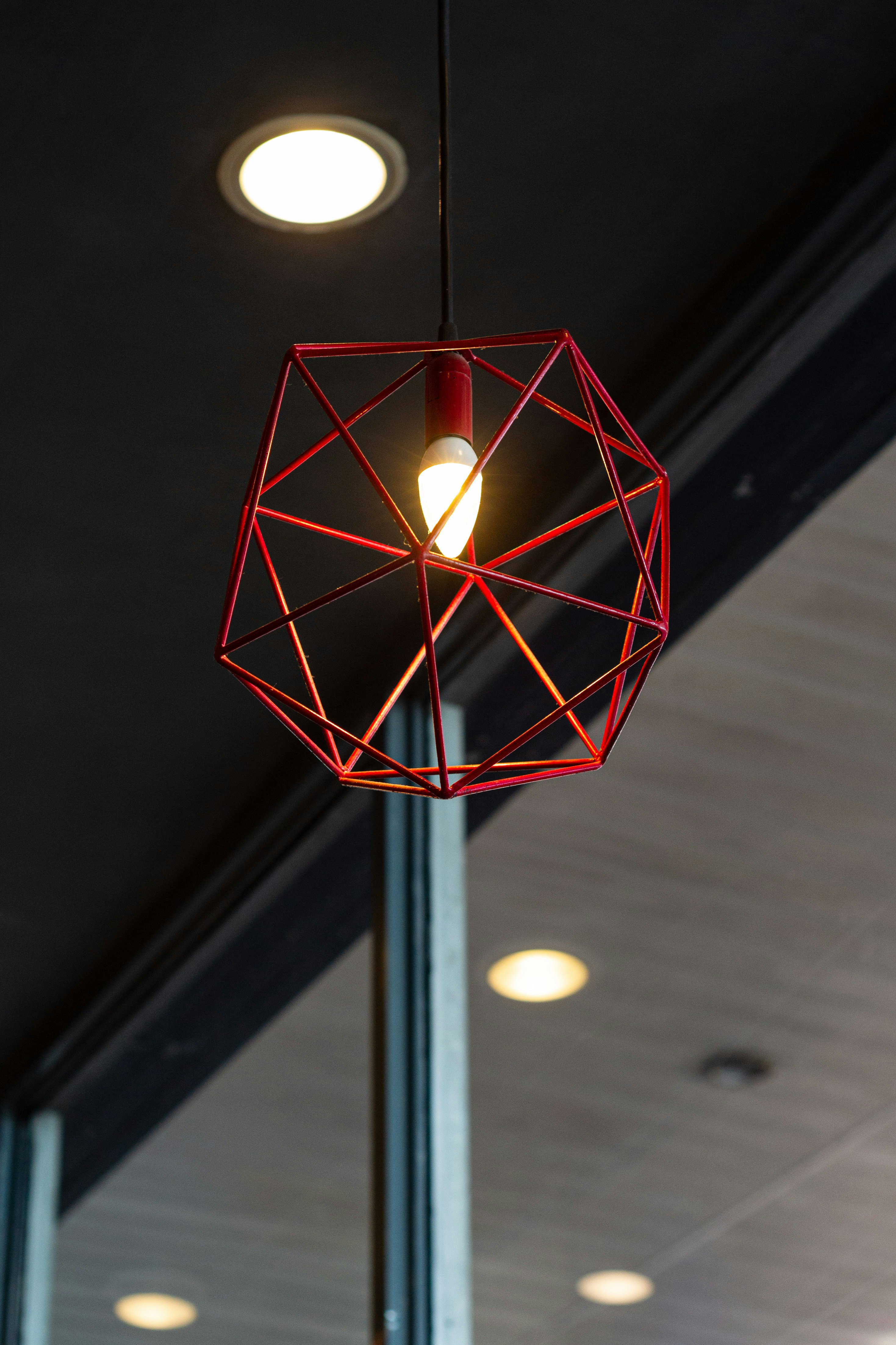 Red geometric pendant light illuminating a contemporary space with soft ambient lighting.