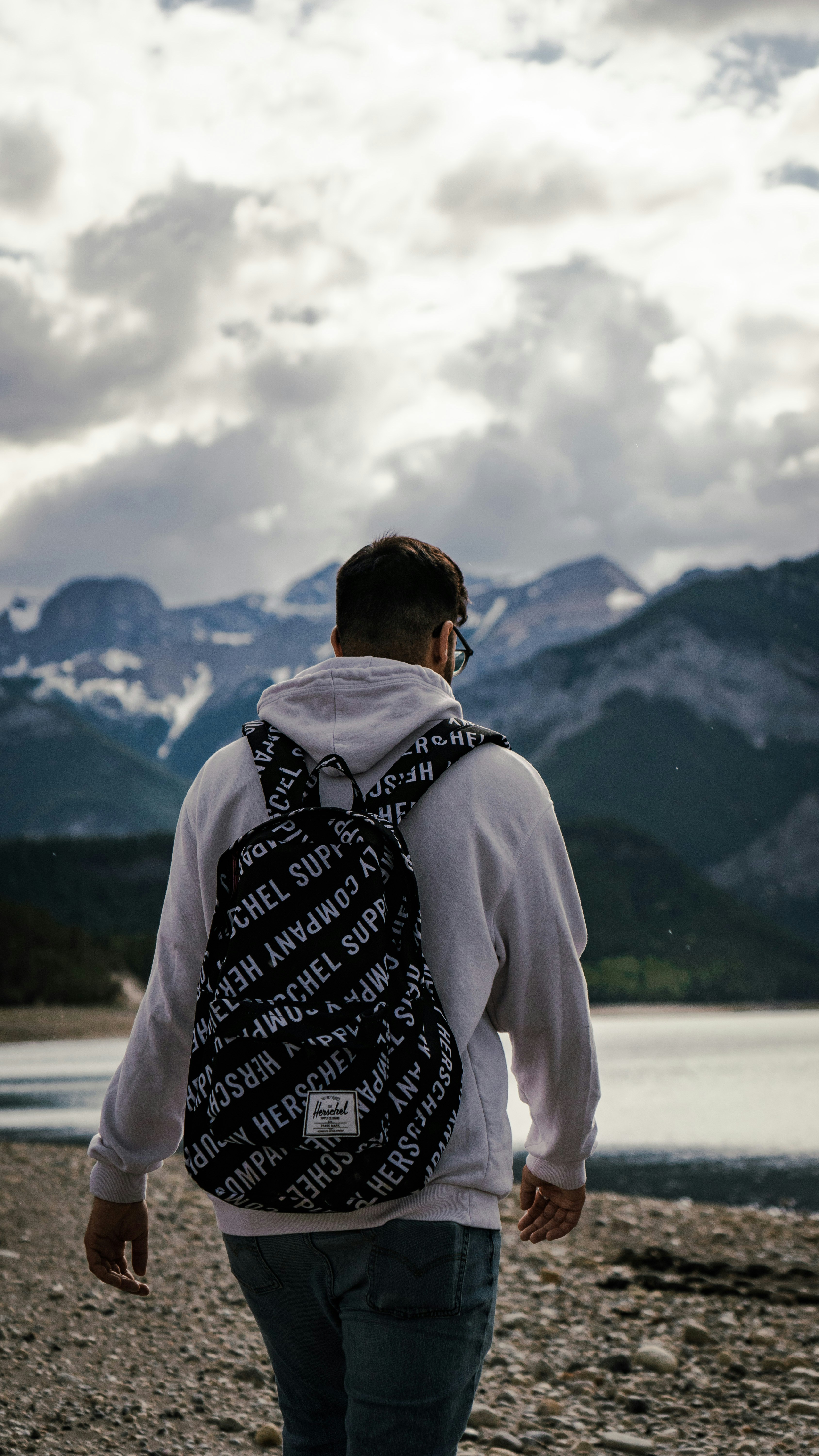 Backpacker at the lakeside edge beneath snow-capped peaks