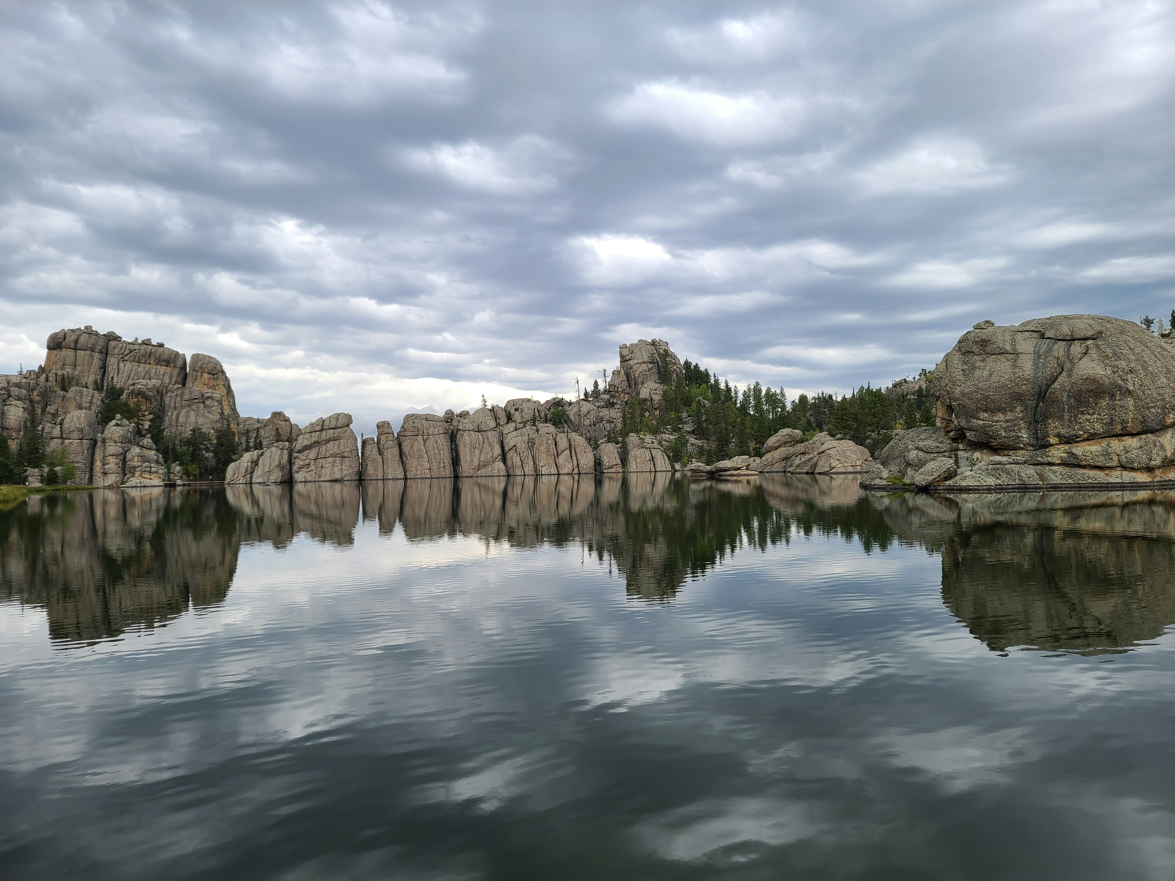 Rock formations mirrored in a serene lake under a cloudy sky, showcasing the beauty of natural landscapes.