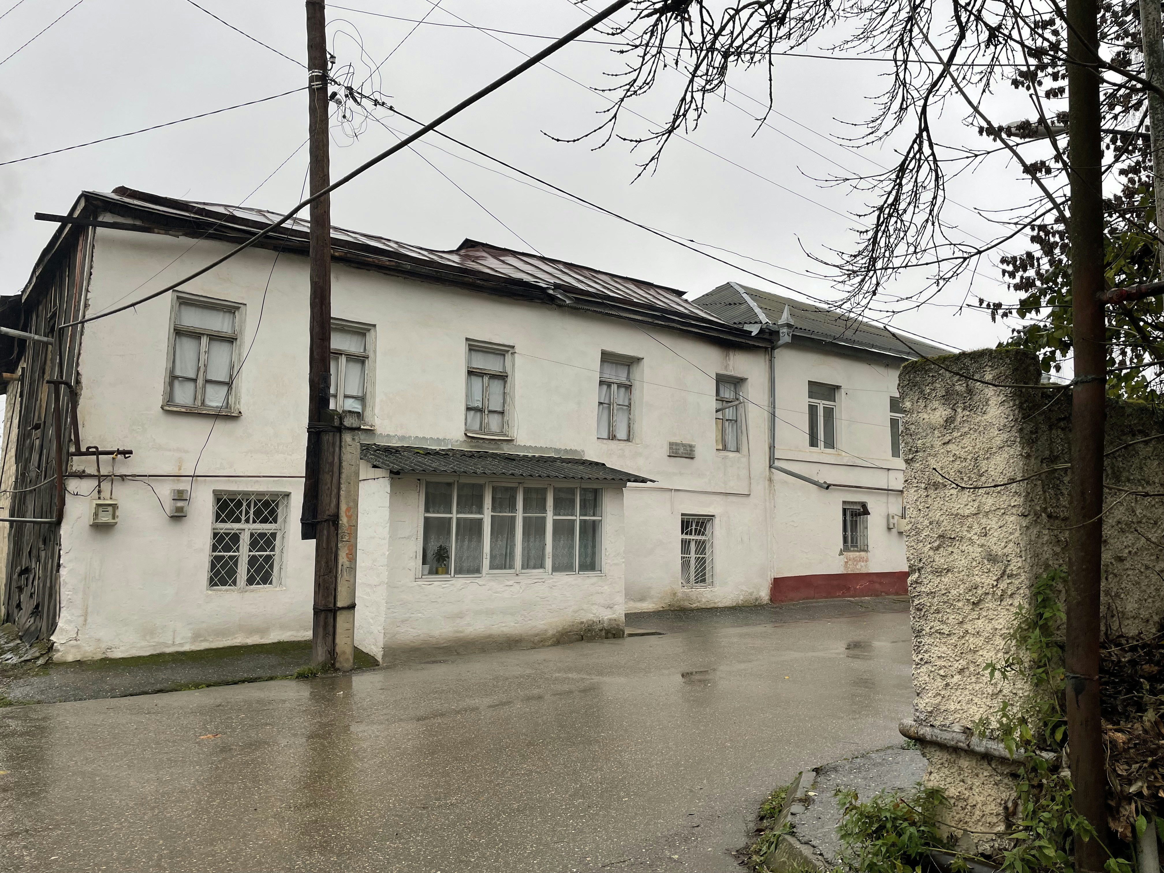 Historic white building on a rainy day with overcast sky and wet pavement.