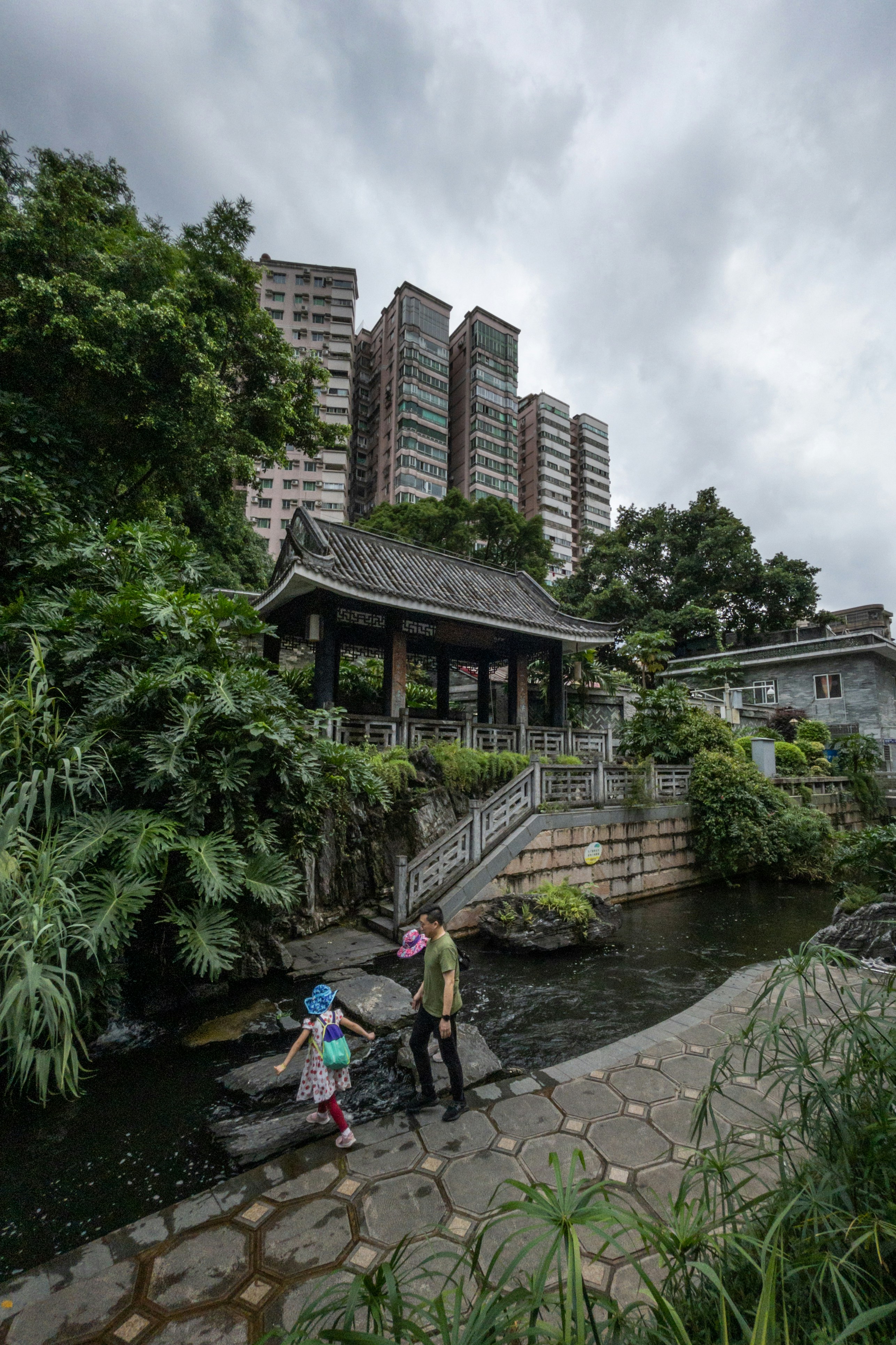 a man and a woman standing on a stone path with a building in the background