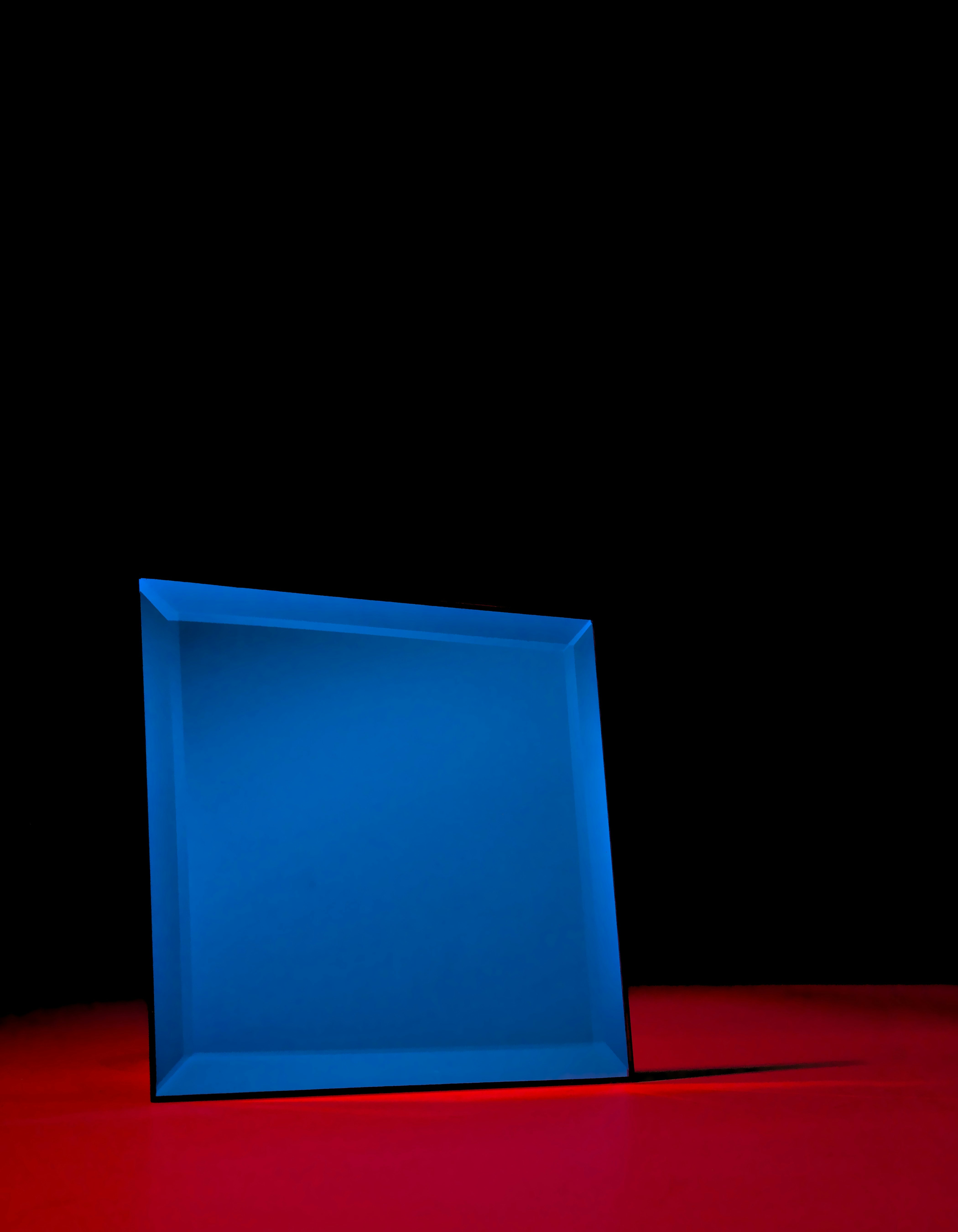 Blue rectangular object on a vibrant red surface against a black background.