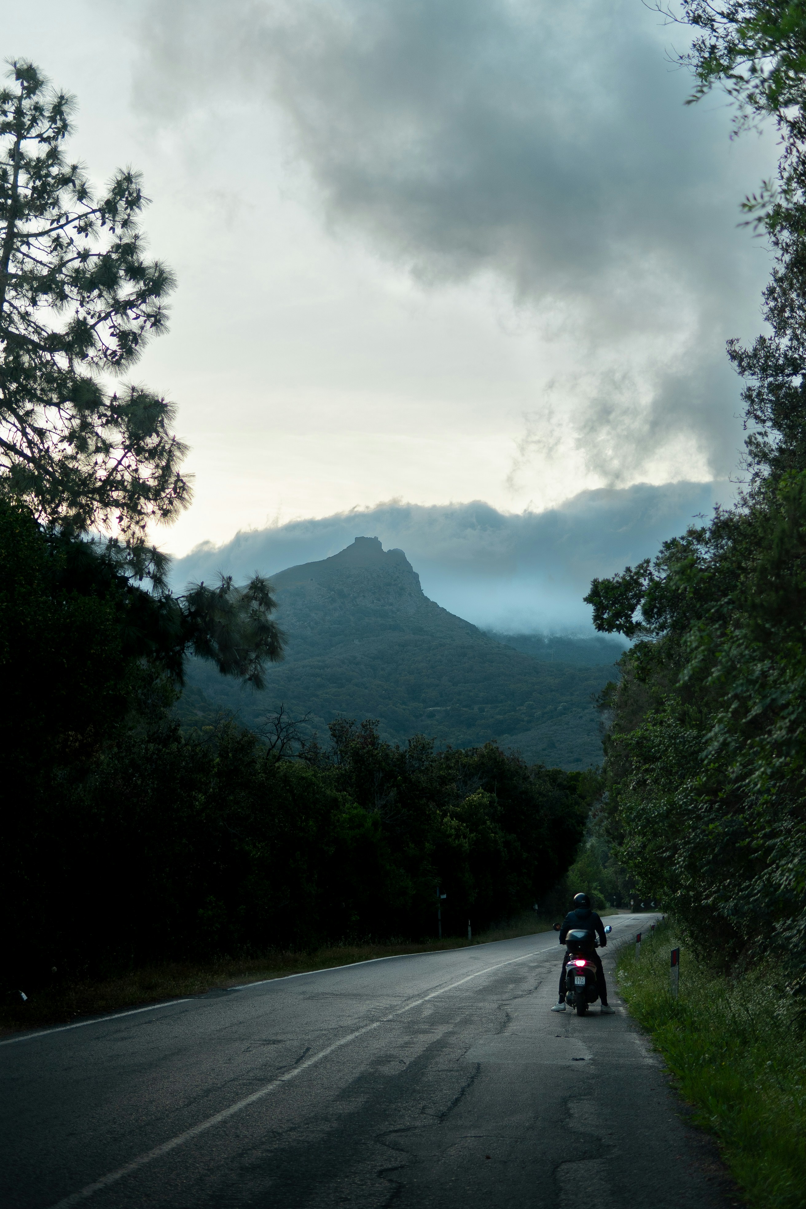 Rider on a mist-wrapped road toward a lone peak