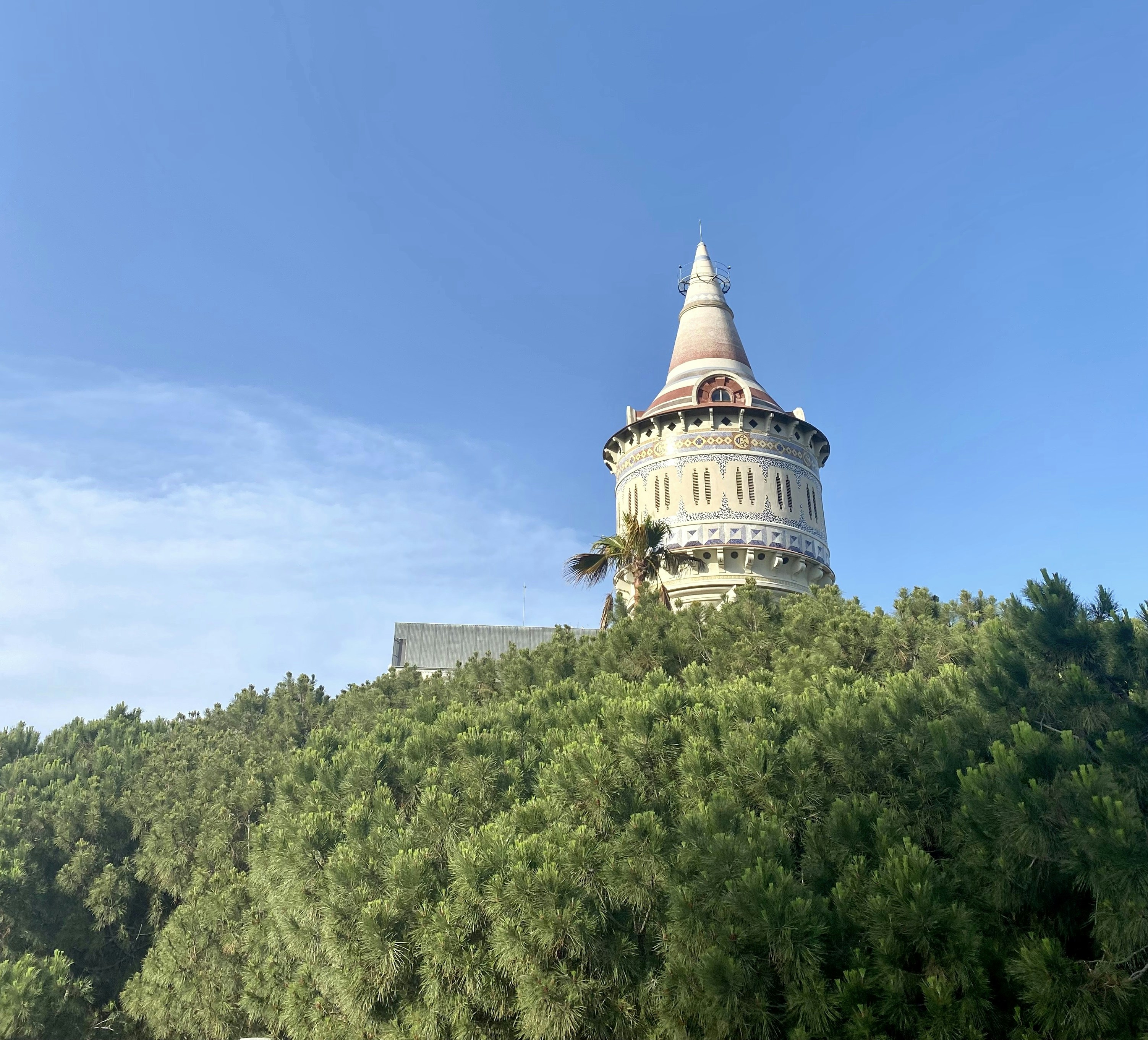 Hilltop Circular Tower Emerges from a Pine Sea Under a Clear Blue Sky