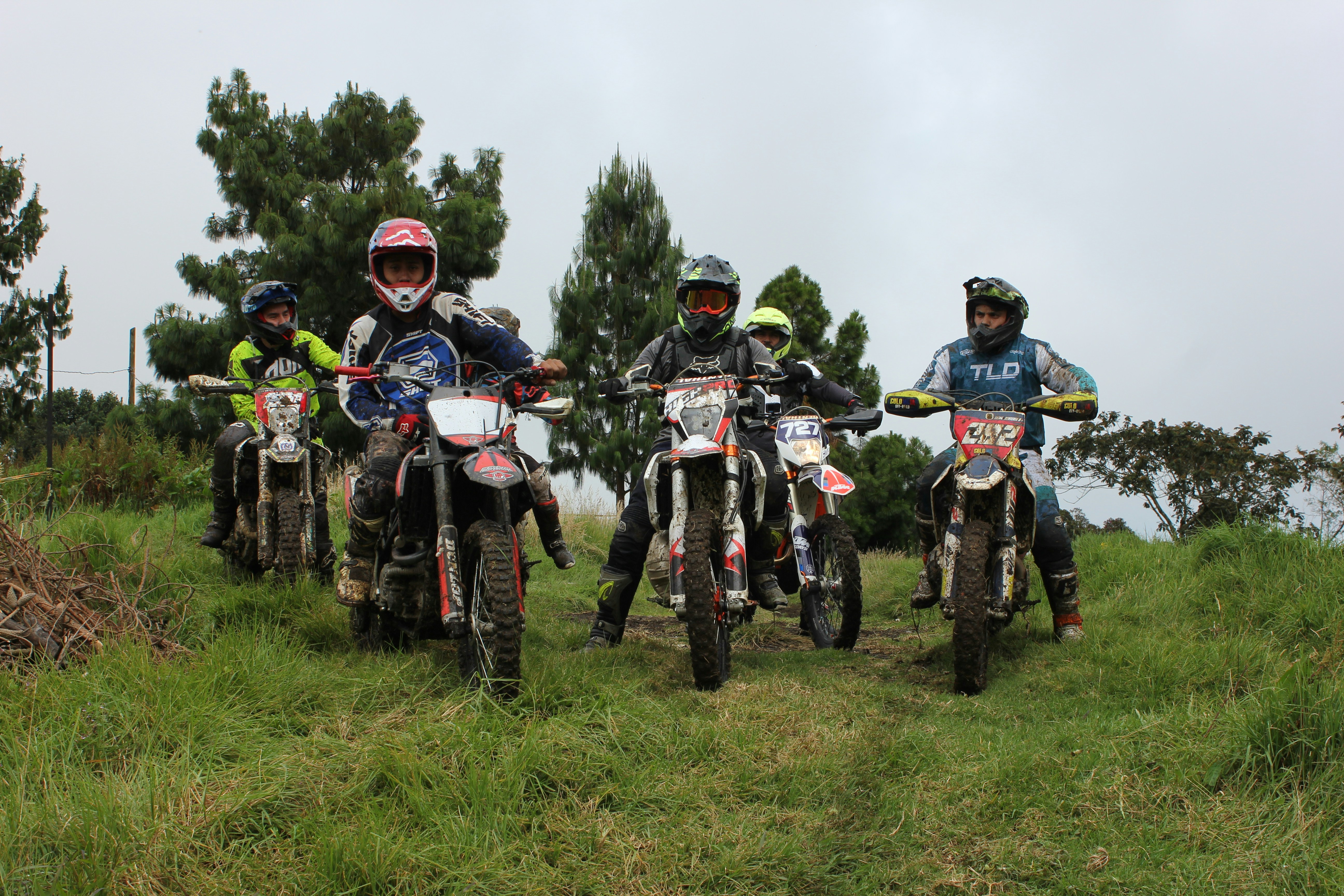 Five Enduro Riders Pause on a Grassy Ridge
